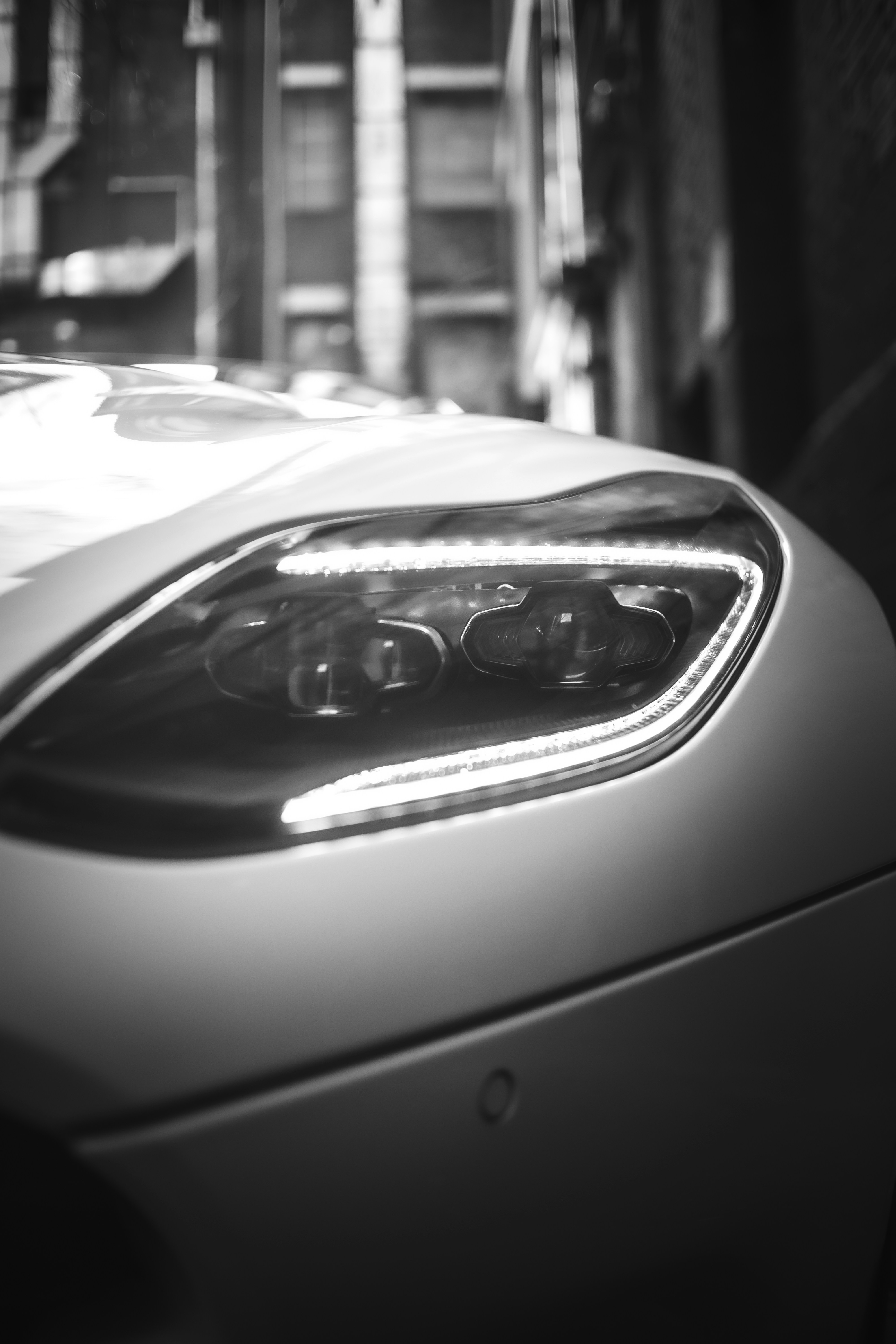 Close-Up of a Car Headlight Amid Urban Backdrop