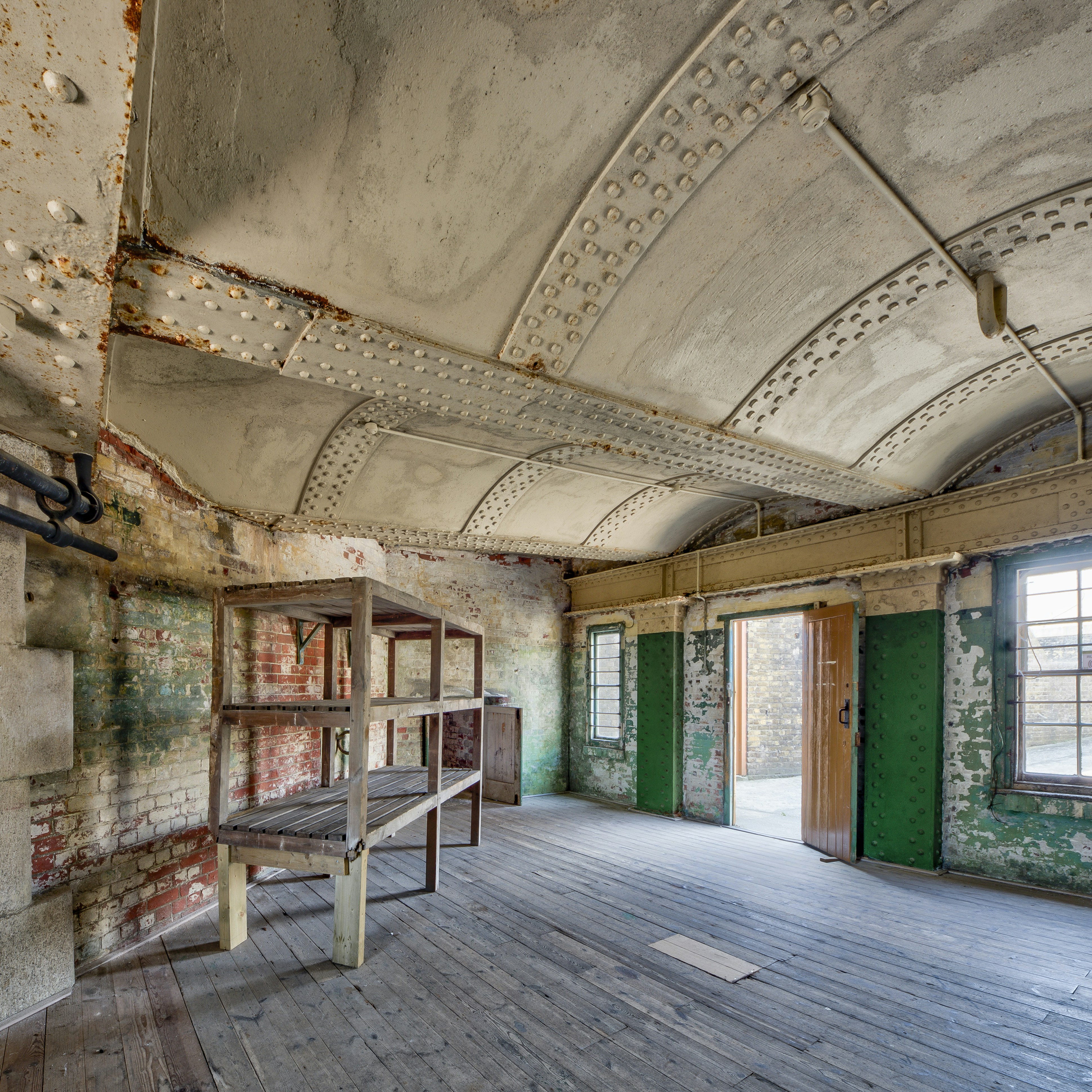 Abandoned upstairs workshop: peeling paint, weathered brick, and a lonely bunk