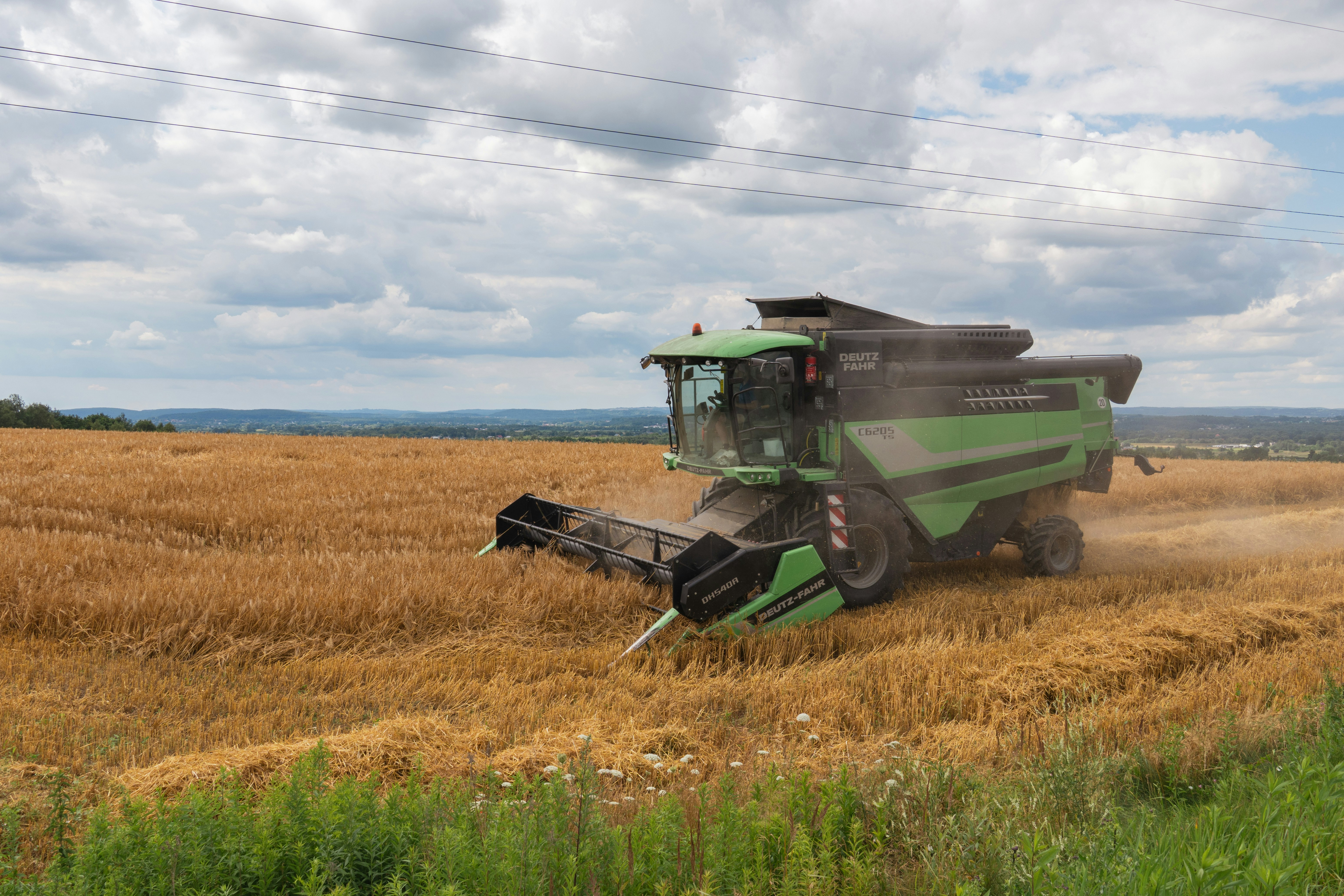 Harvesting Giant: Green Combine in a Golden Field Under Wide Skies