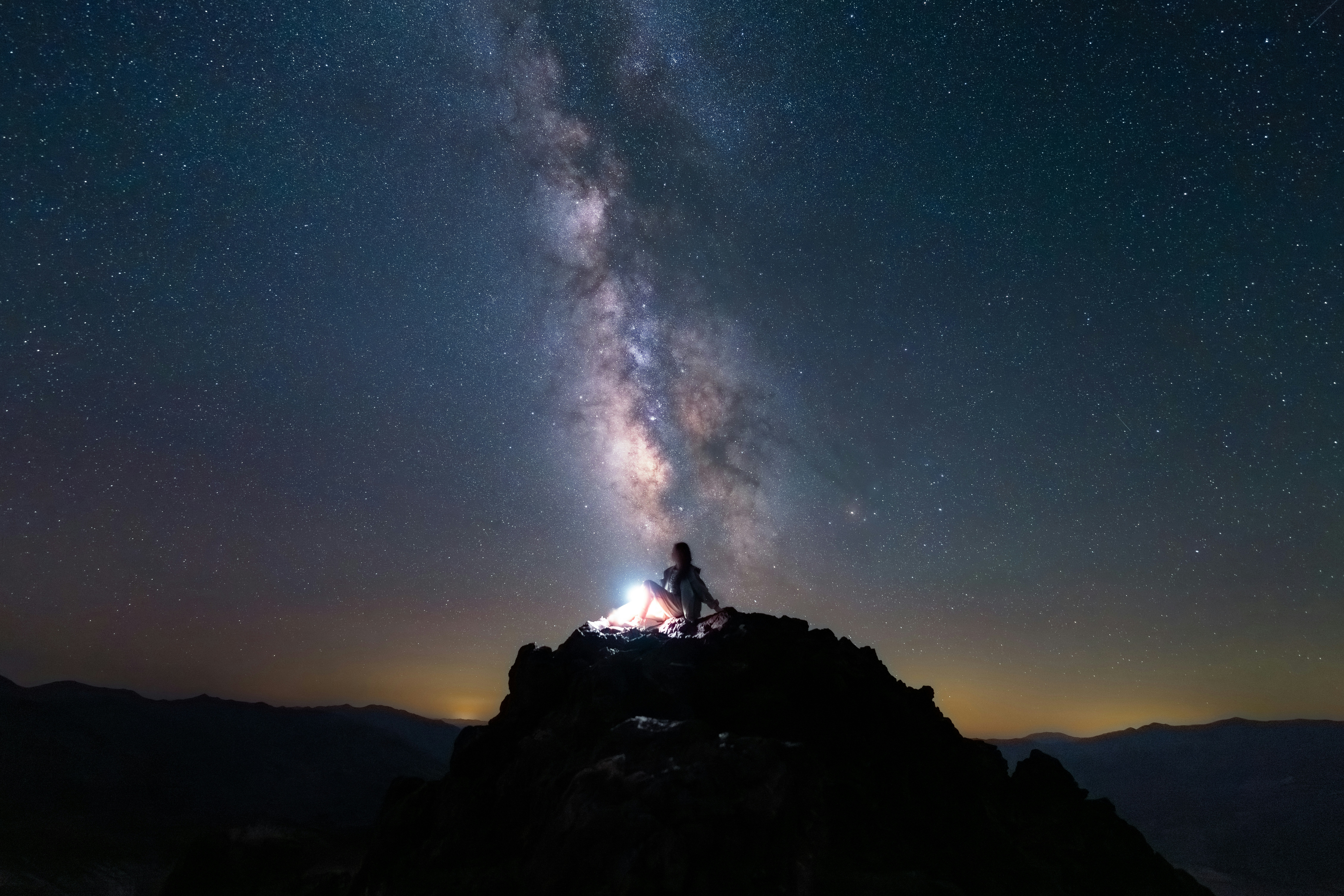 Milky Way Ascent: Night climber atop a rocky crest beneath a stellar river