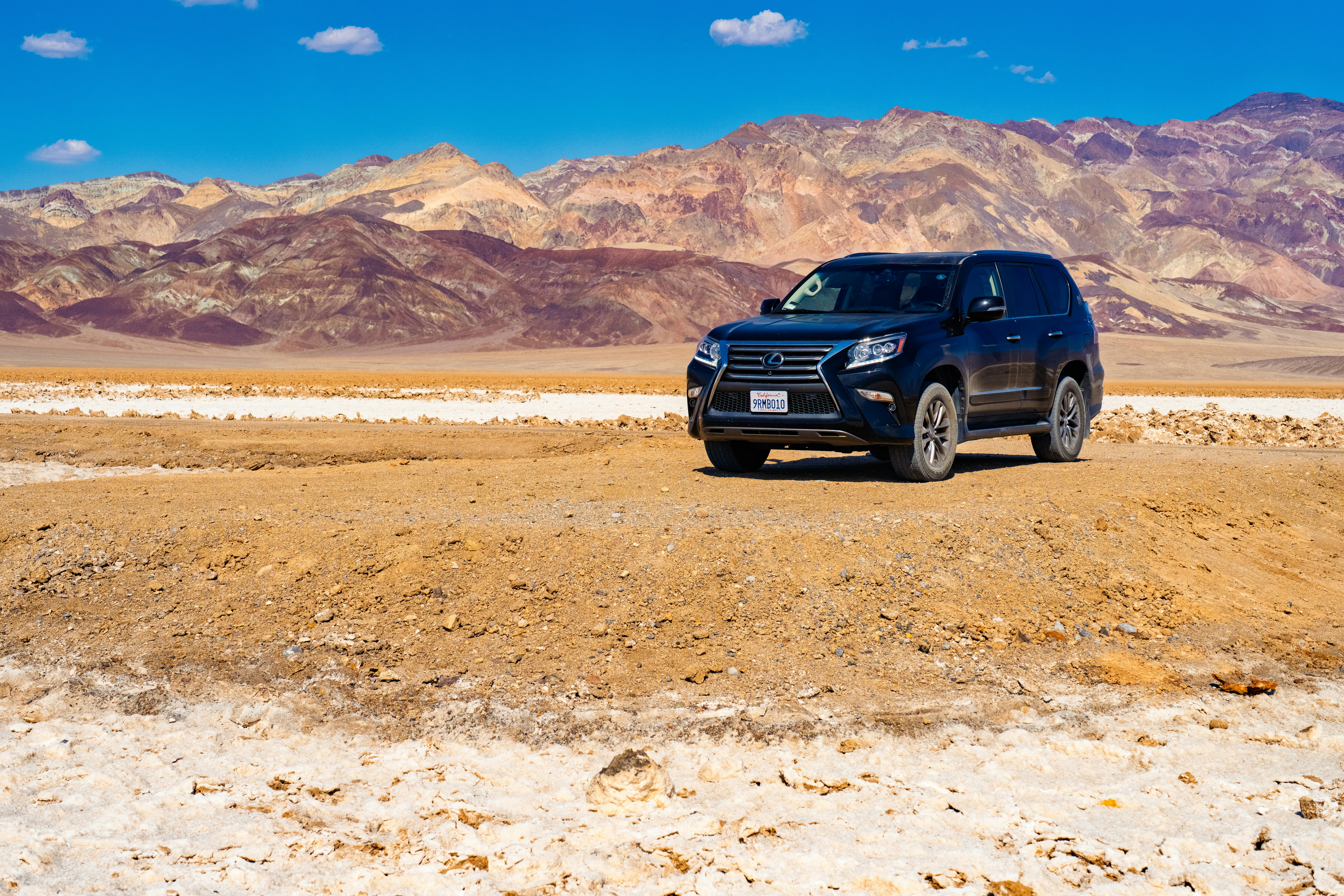 Desert Highway: A Dark SUV Anchors the Scene Against Amethyst Mountains