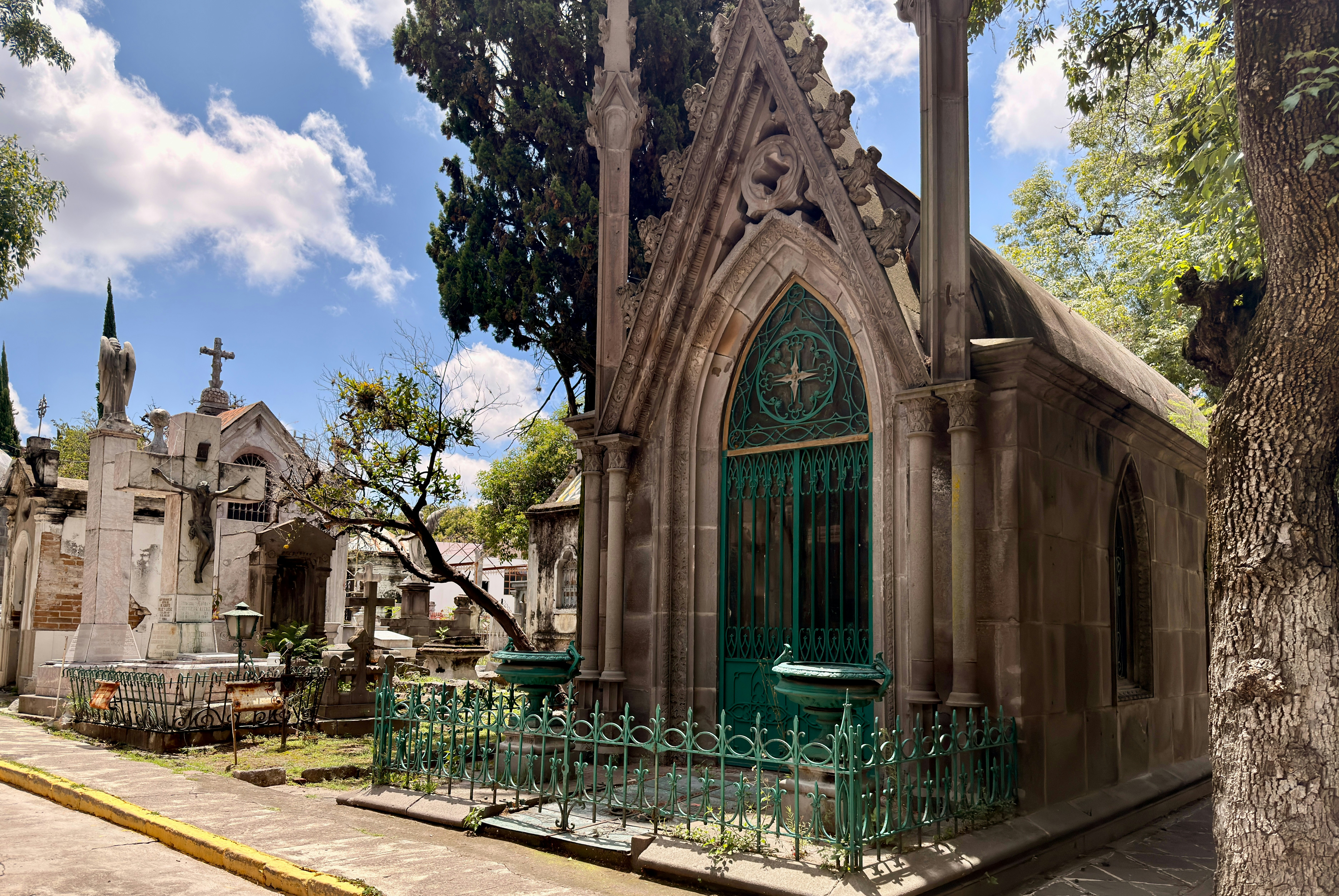 Gothic Chapel in a sunlit courtyard bordered by weathered tombs