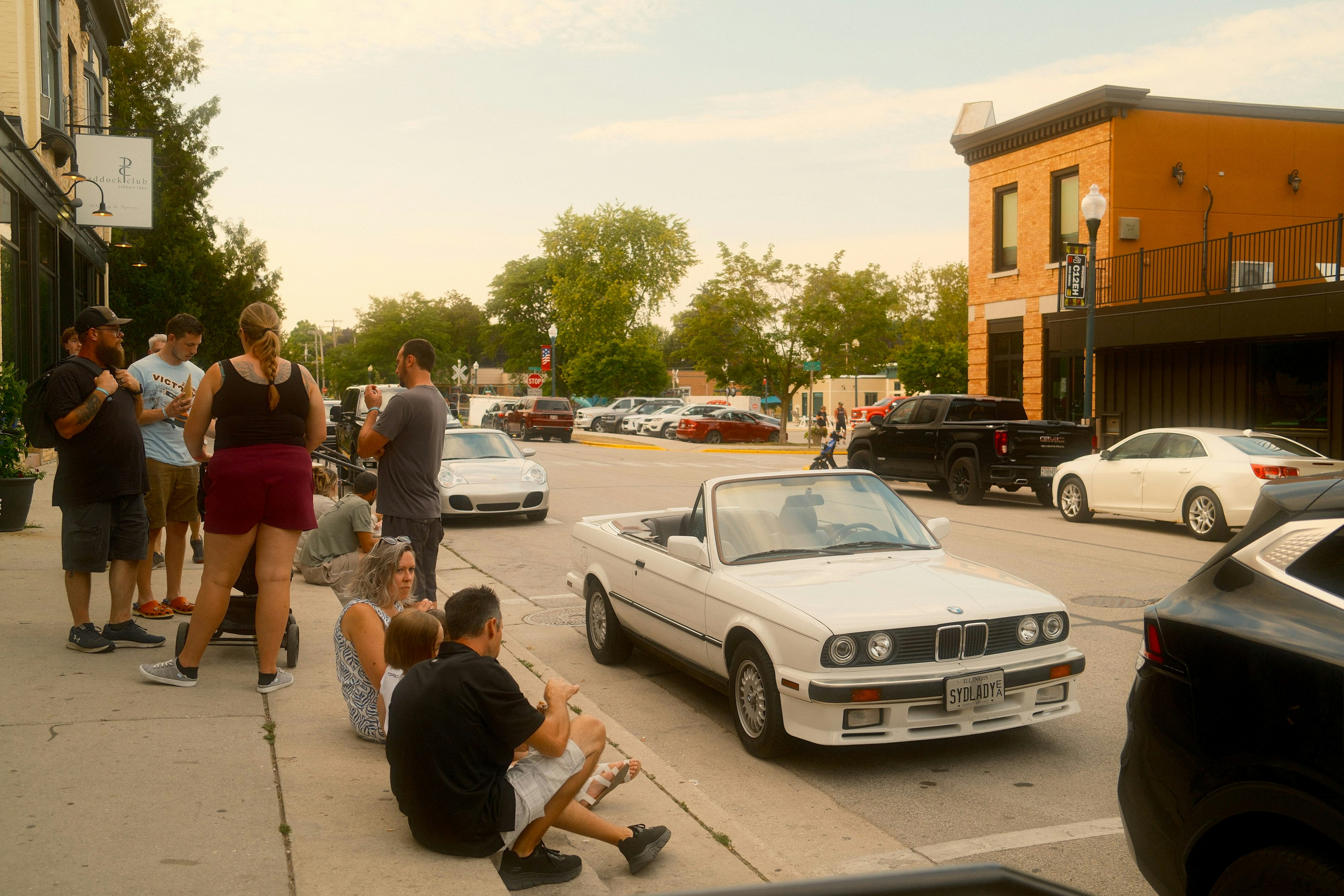 Low-Slung Street Gathering by a White Convertible