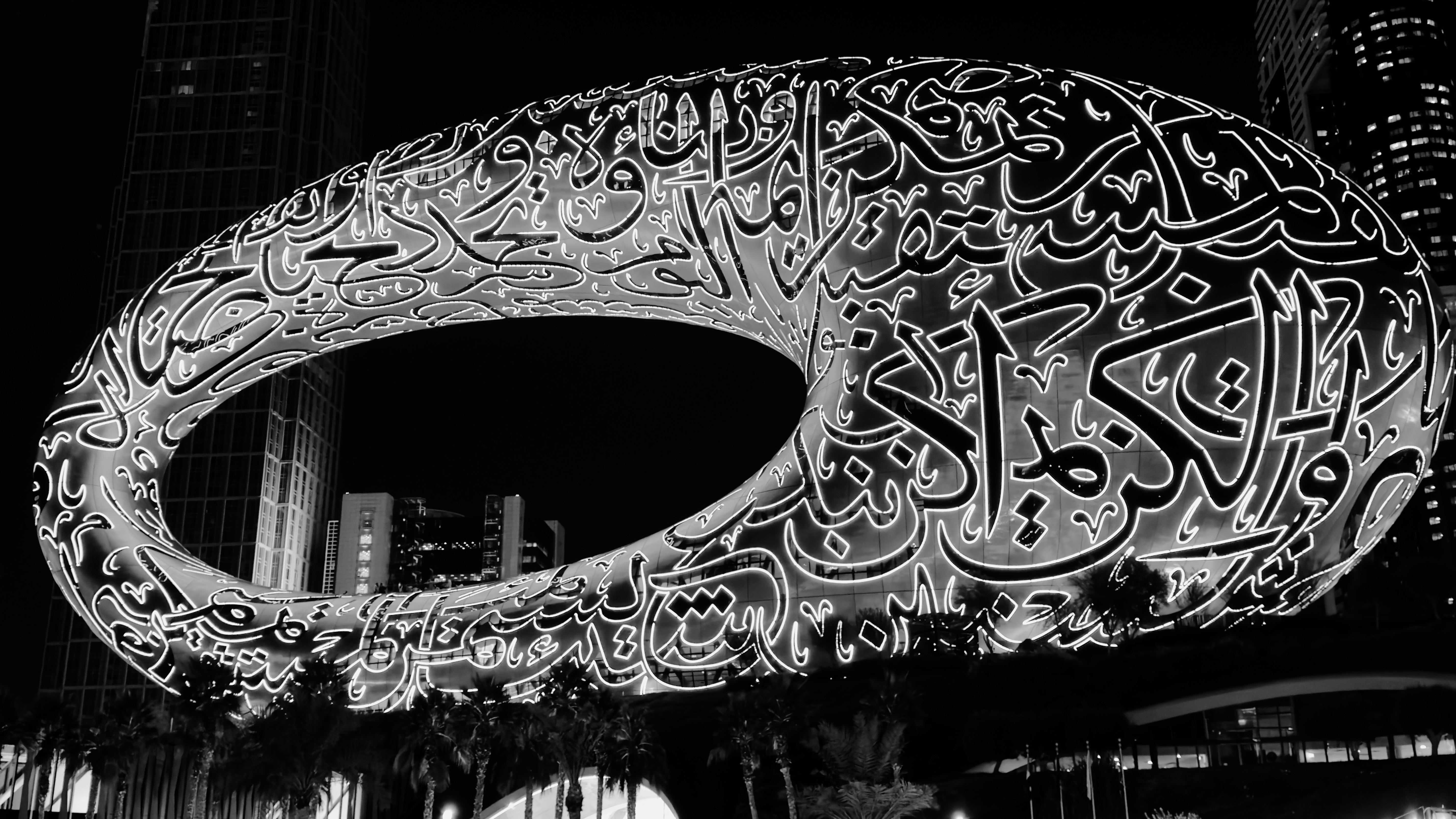 Luminous Loop: Arabic Calligraphy Sculpture Framing the Night Skyline