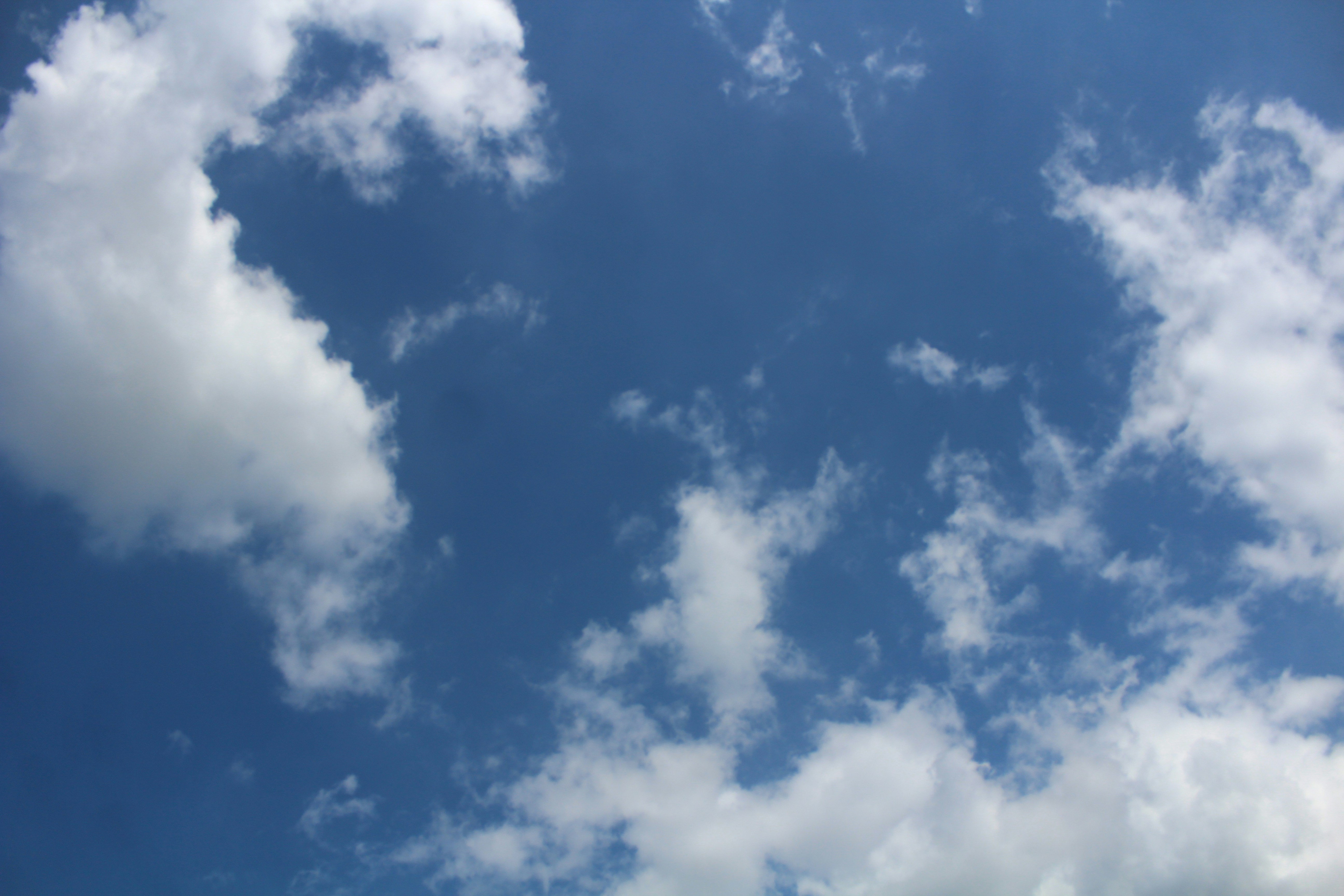Bright blue sky with scattered white cumulus clouds, minimal foreground details, emphasizing airy atmosphere.