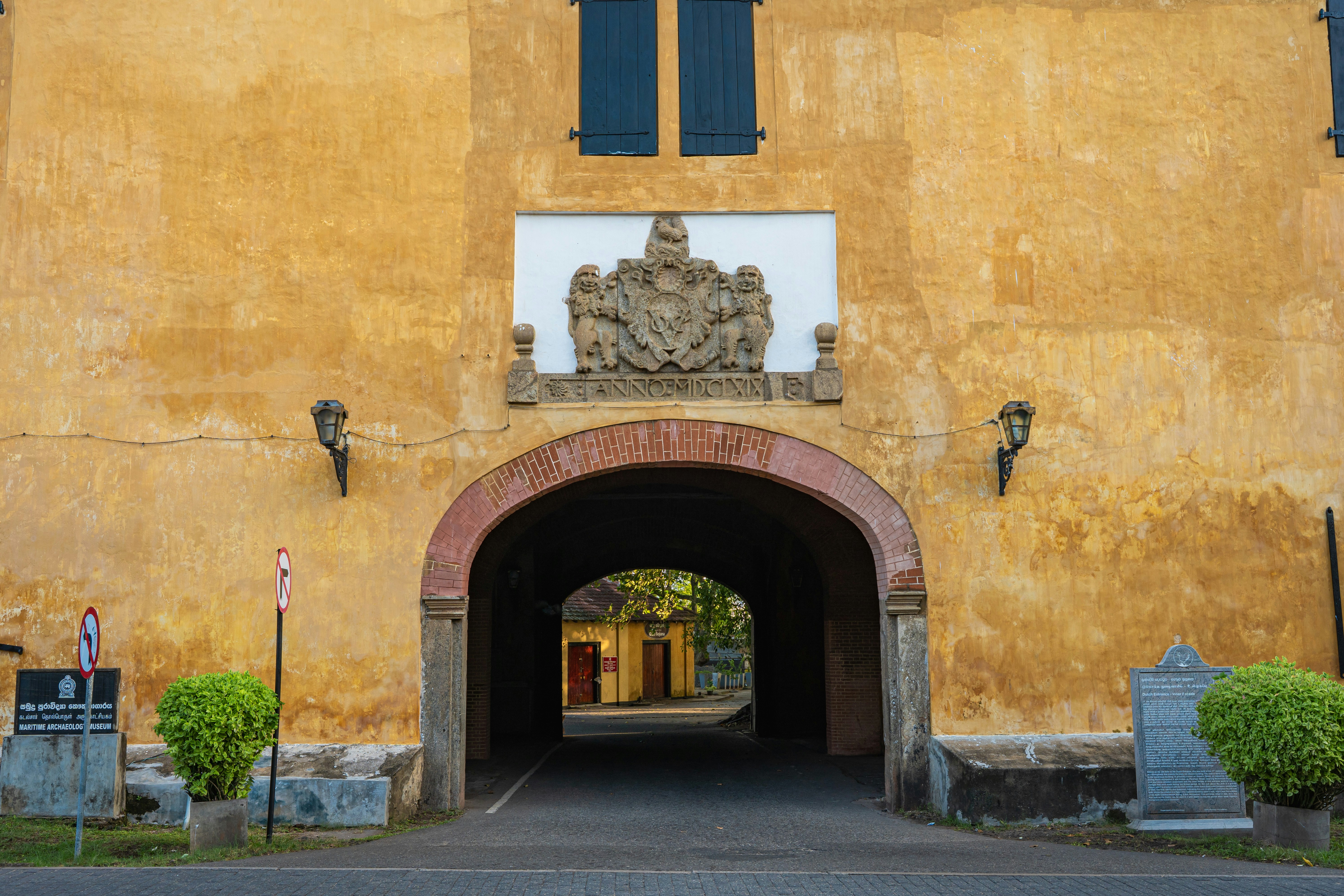 Gateway of Colors and Crest: A Historic Archway in Warm Yellow