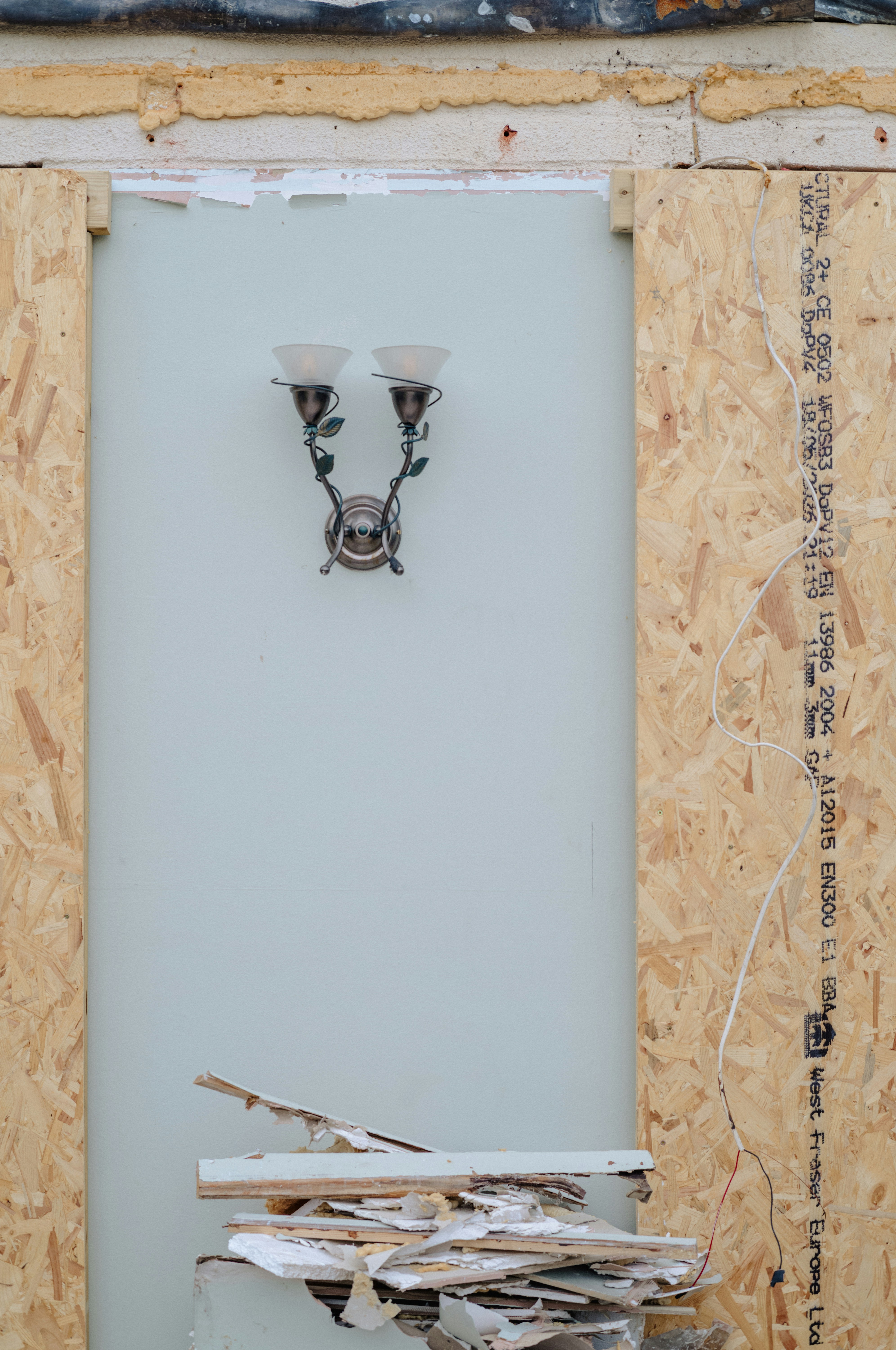 Wall sconce on blue wall amidst renovation debris