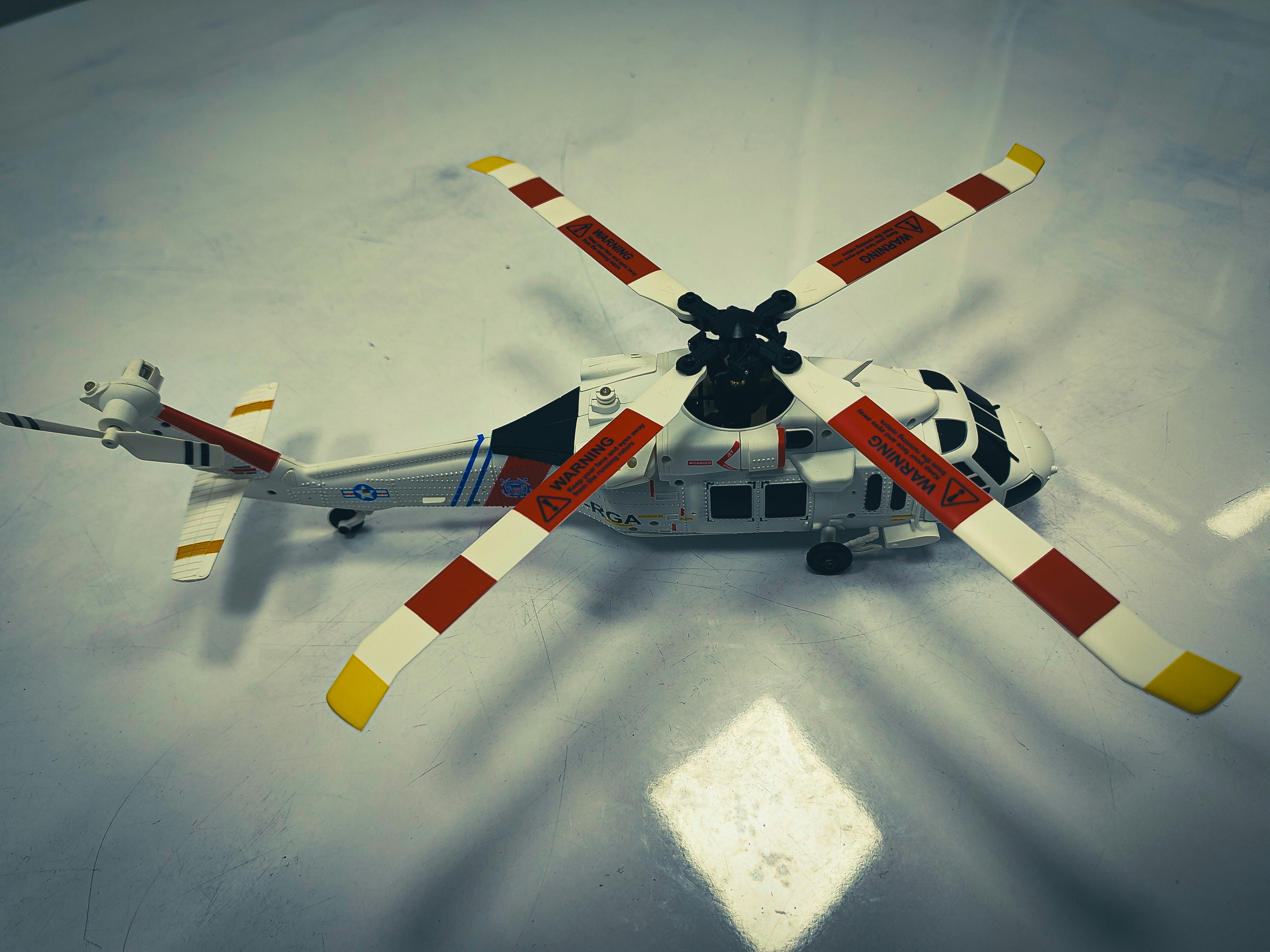 Colorful toy helicopter with red‑and‑white rotor blades on a pale surface