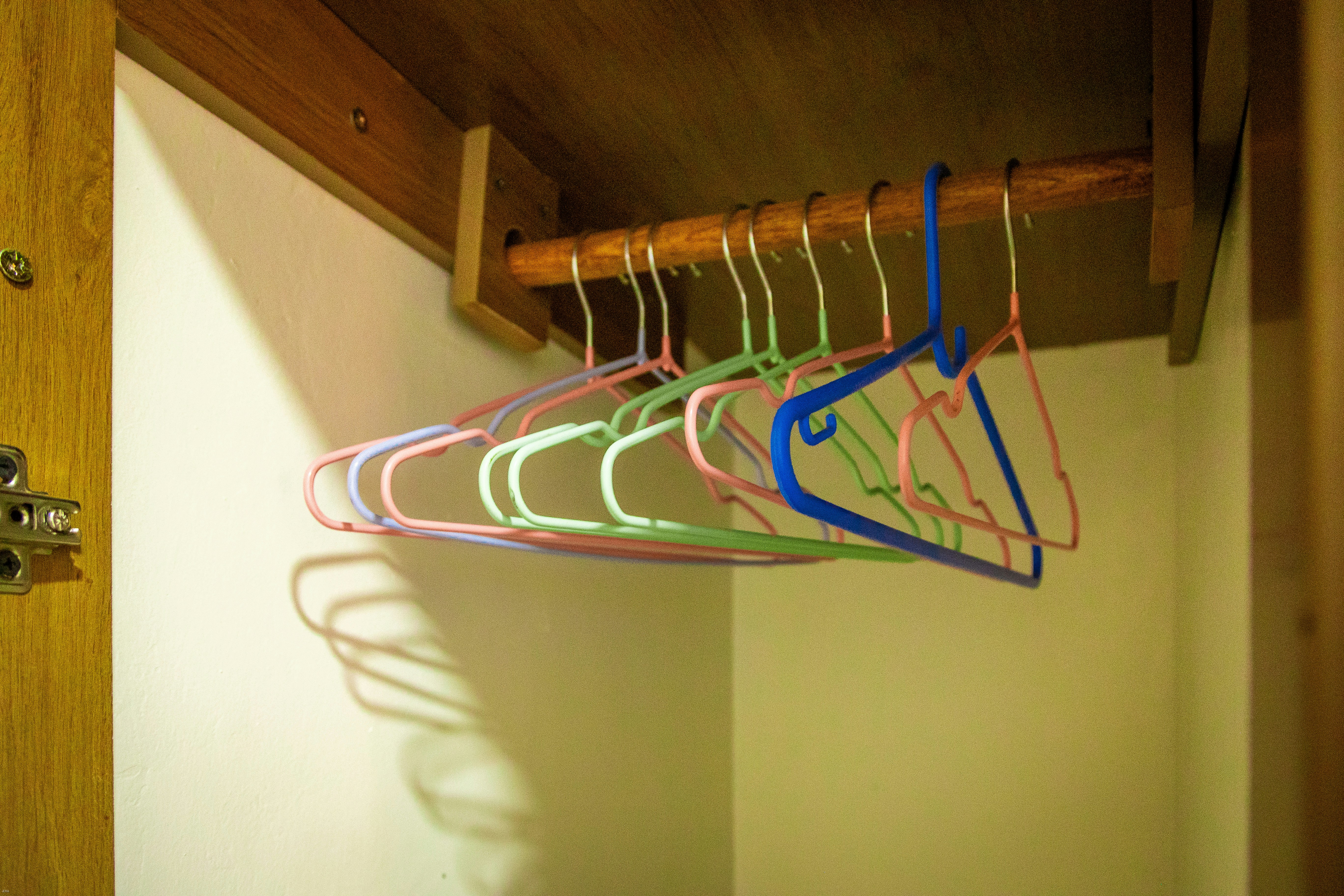 Colorful clothes hangers casting soft shadows inside a wardrobe alcove