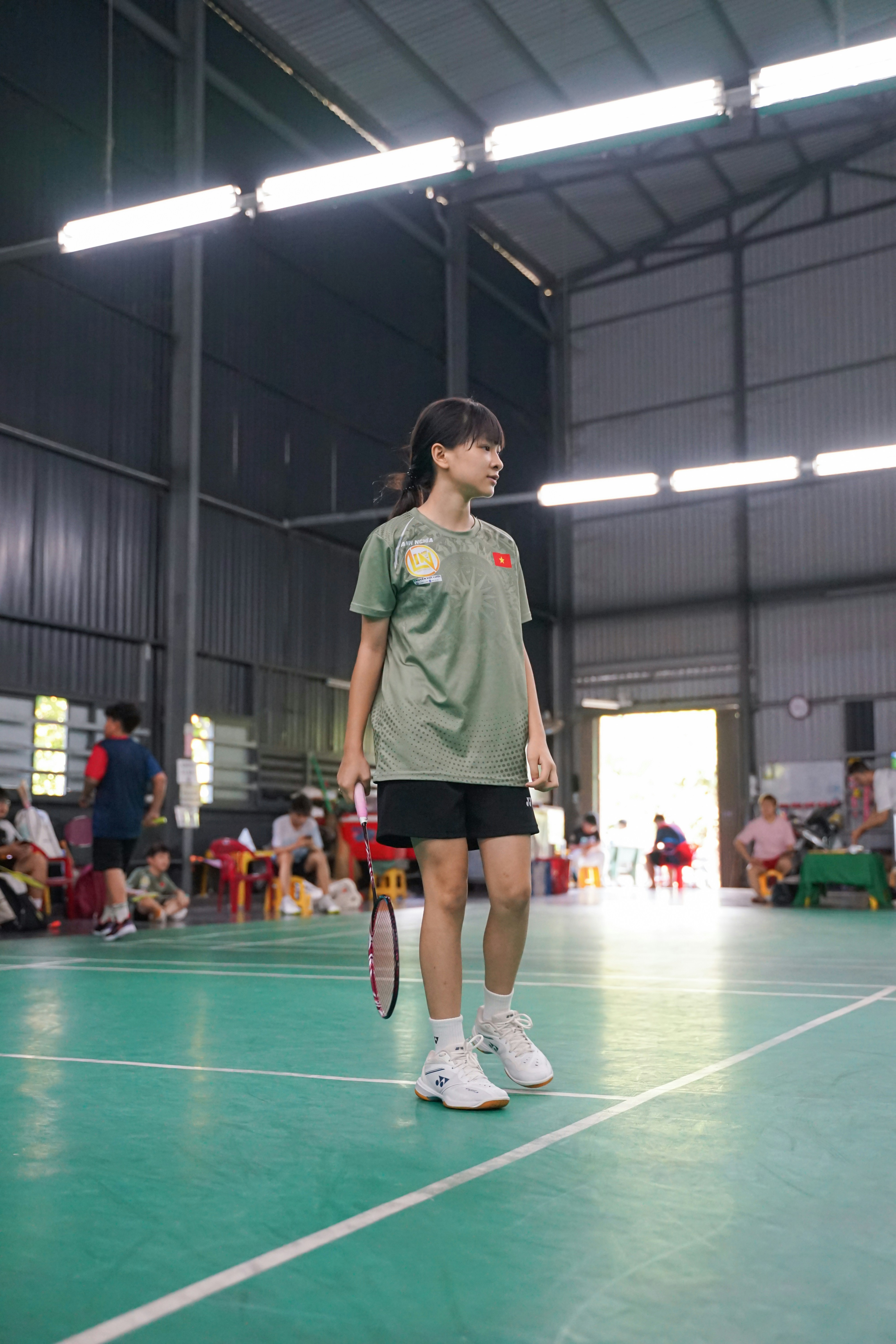 Center Court: A badminton player stands poised in a gym