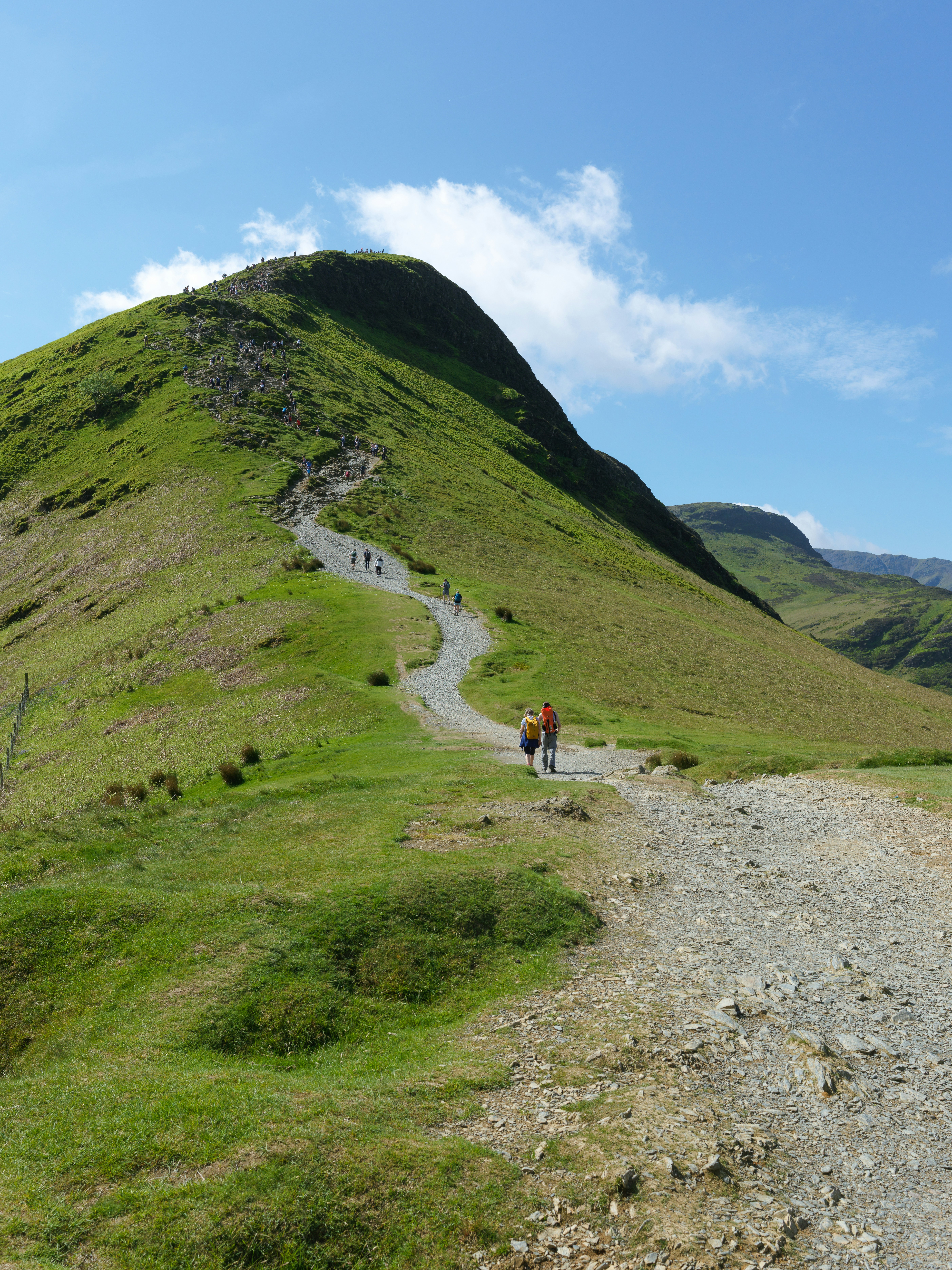 Hikers Ascent the Green Ridge under a Clear Sky