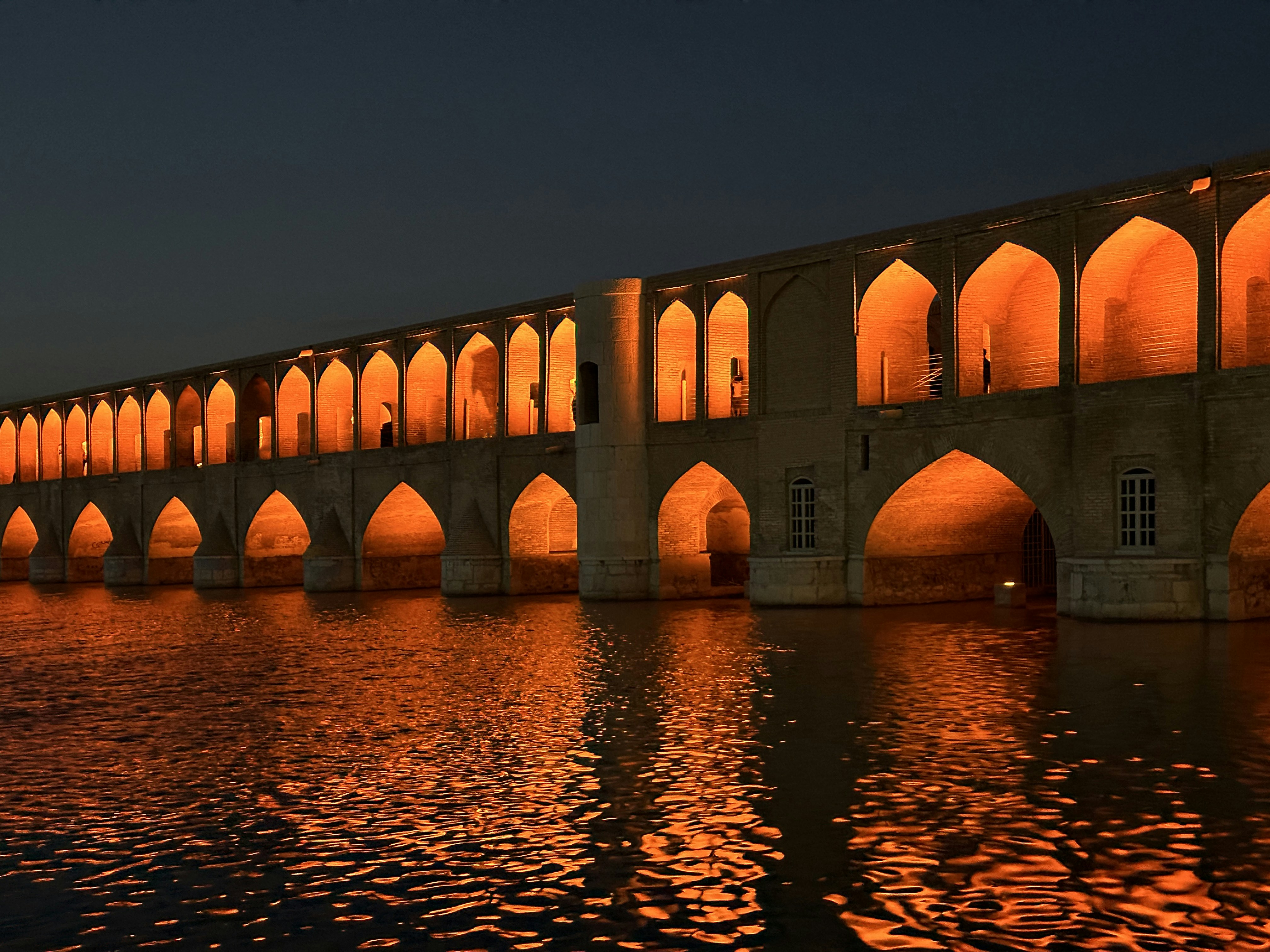 Moonlit Arcades: A Bricked Bridge Over Firelight Waters