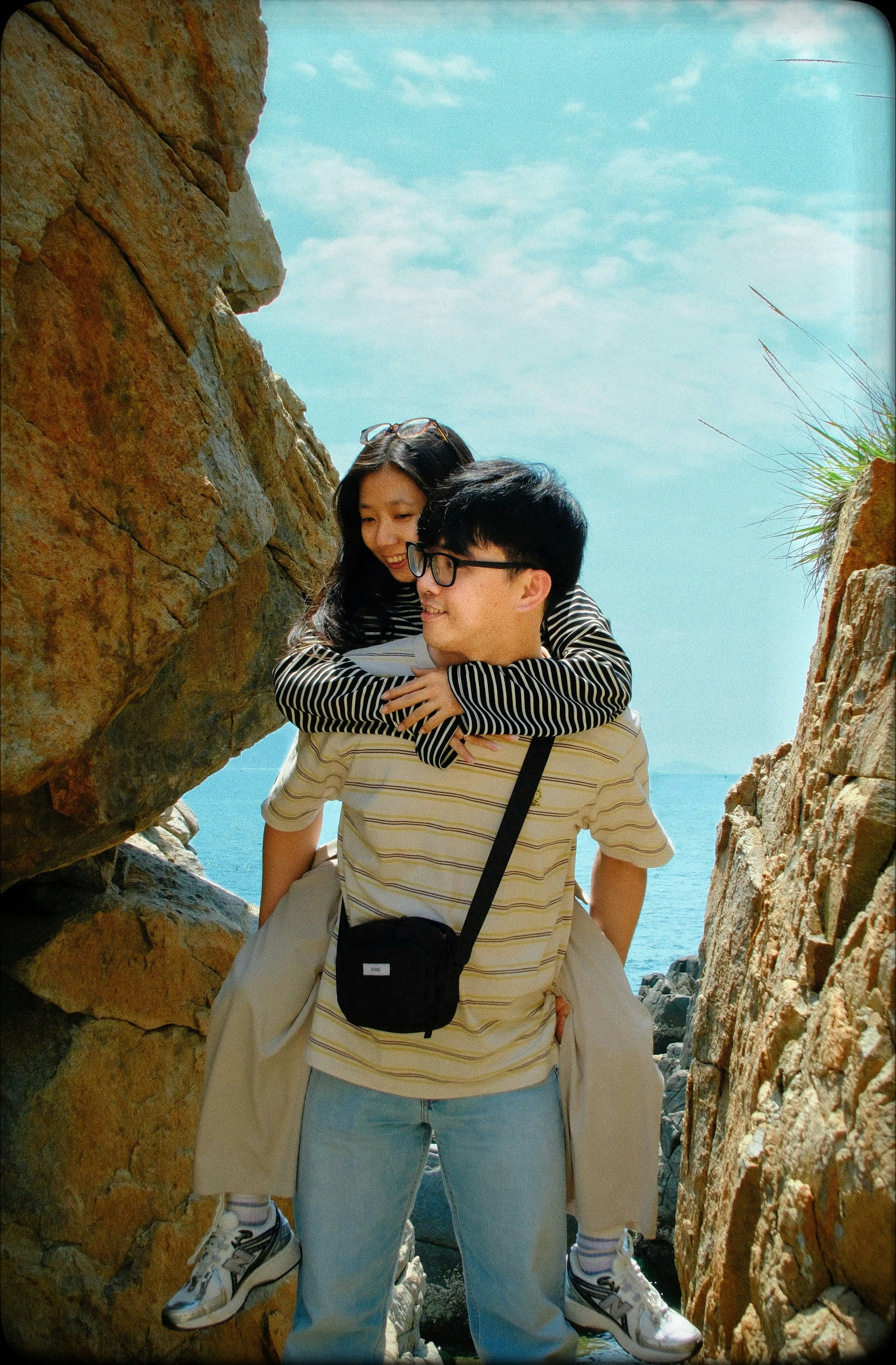 Two in a Coastal Cliff Hug: A Playful Carry Across the Rocks