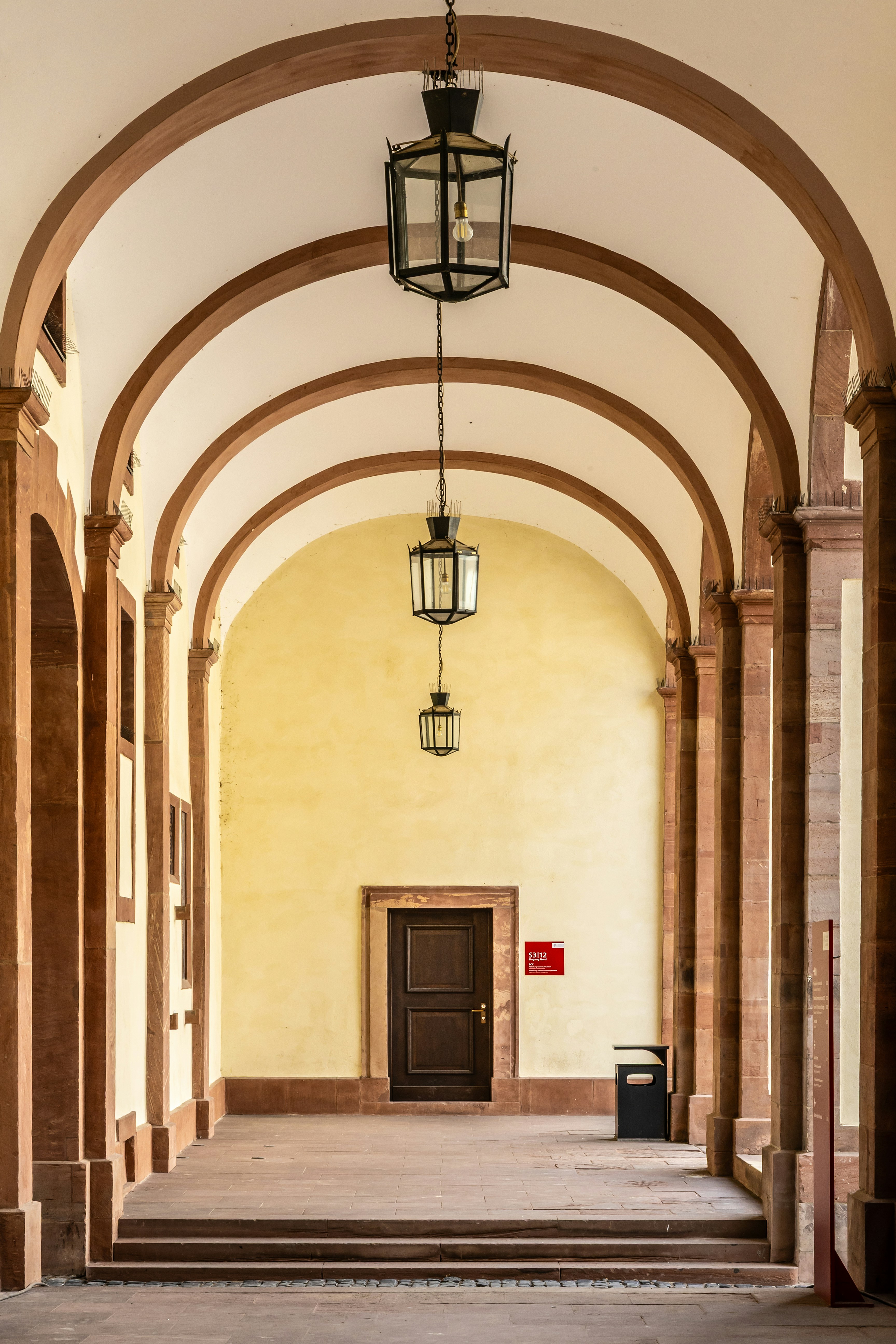 Arched Corridor: Hanging Lanterns and Quiet Doorway
