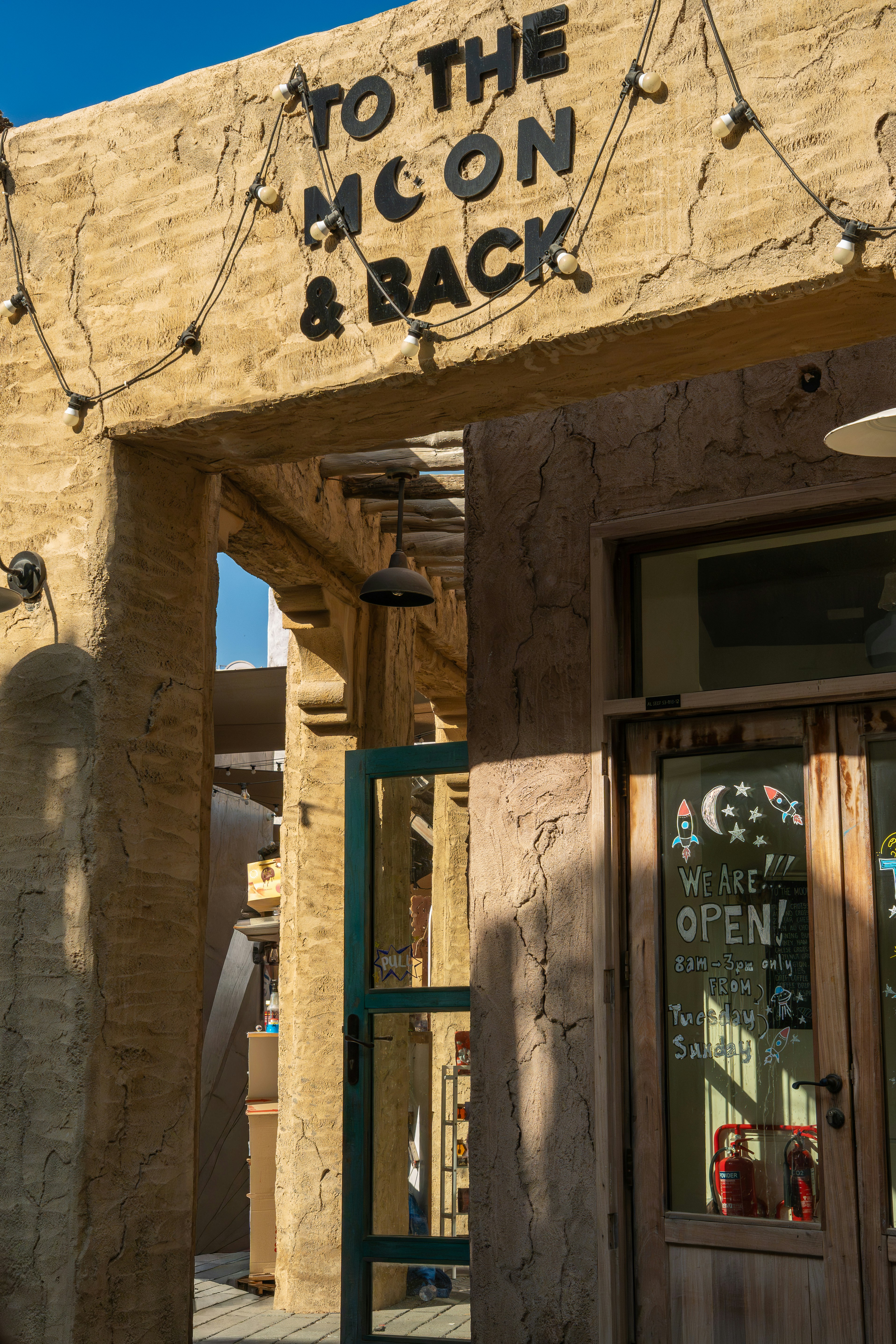 Open Sign, Stone Archway: A Sunlit Entrance to a Desert Shop