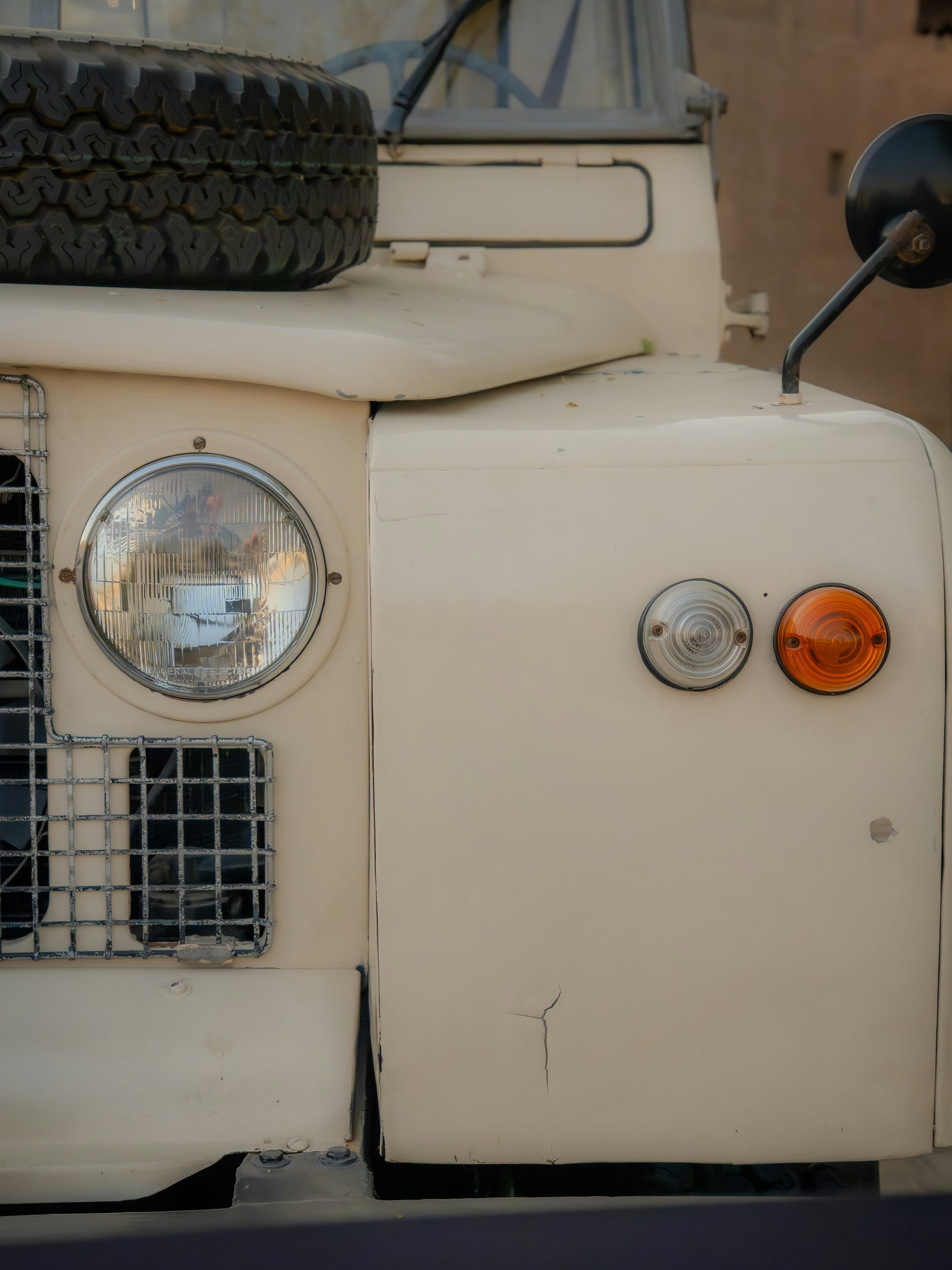 Front-Quarter Vintage Vehicle: Weathered Beige Front with Spare Tire