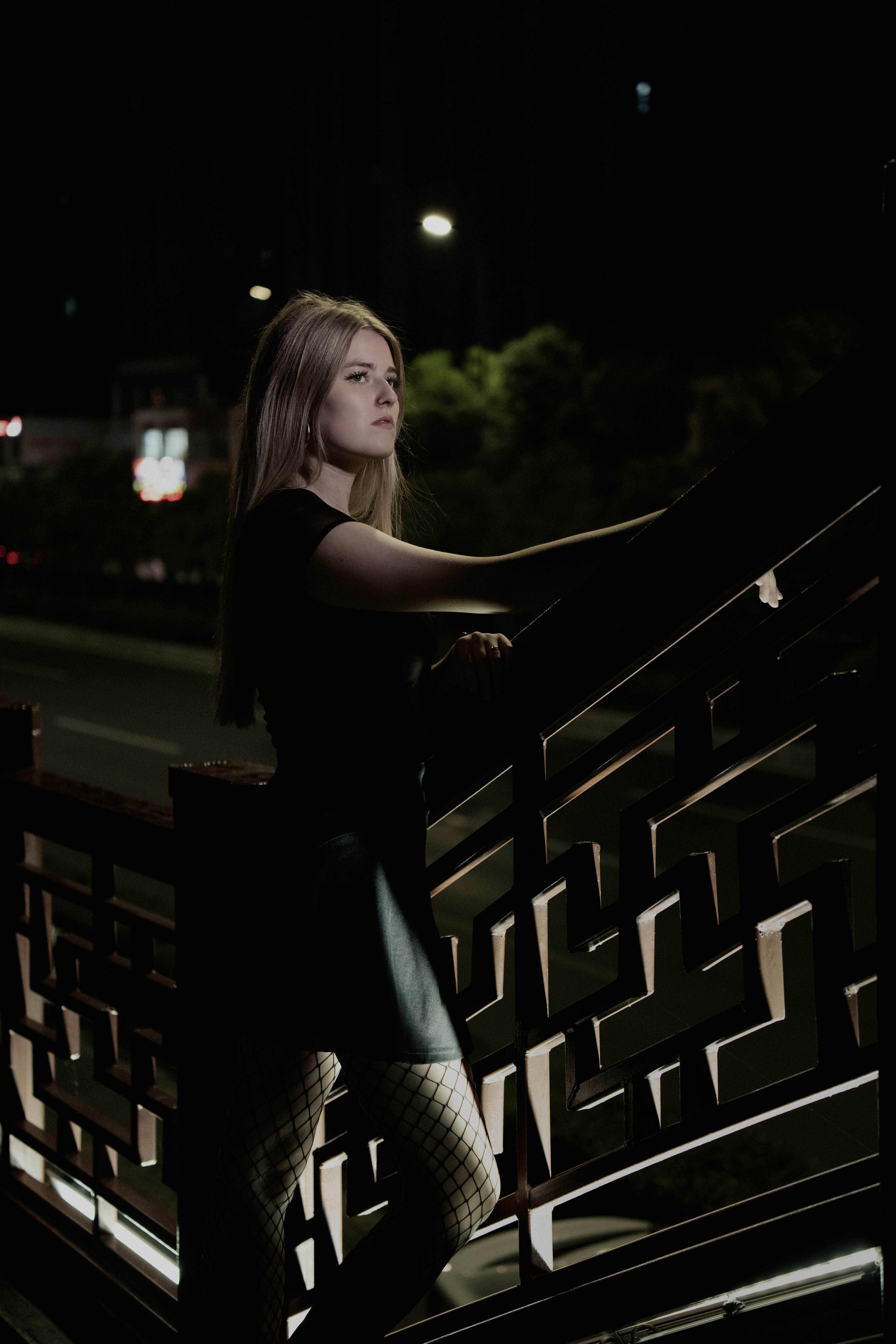 Moonlit Balcony: A Portrait Against Urban Nightlight