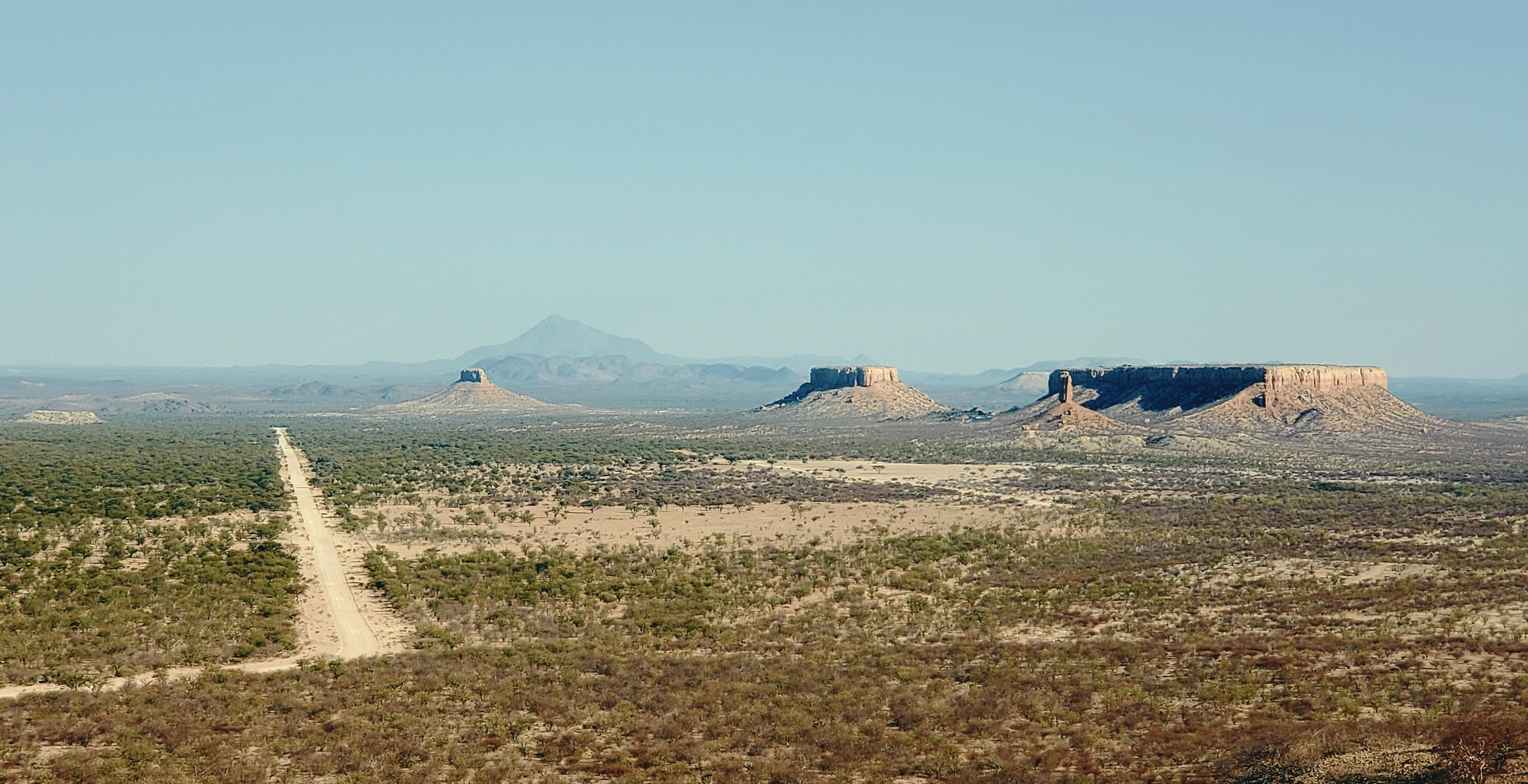 Desert Ridge Horizon: Distant Buttes and a Winding Dust Road