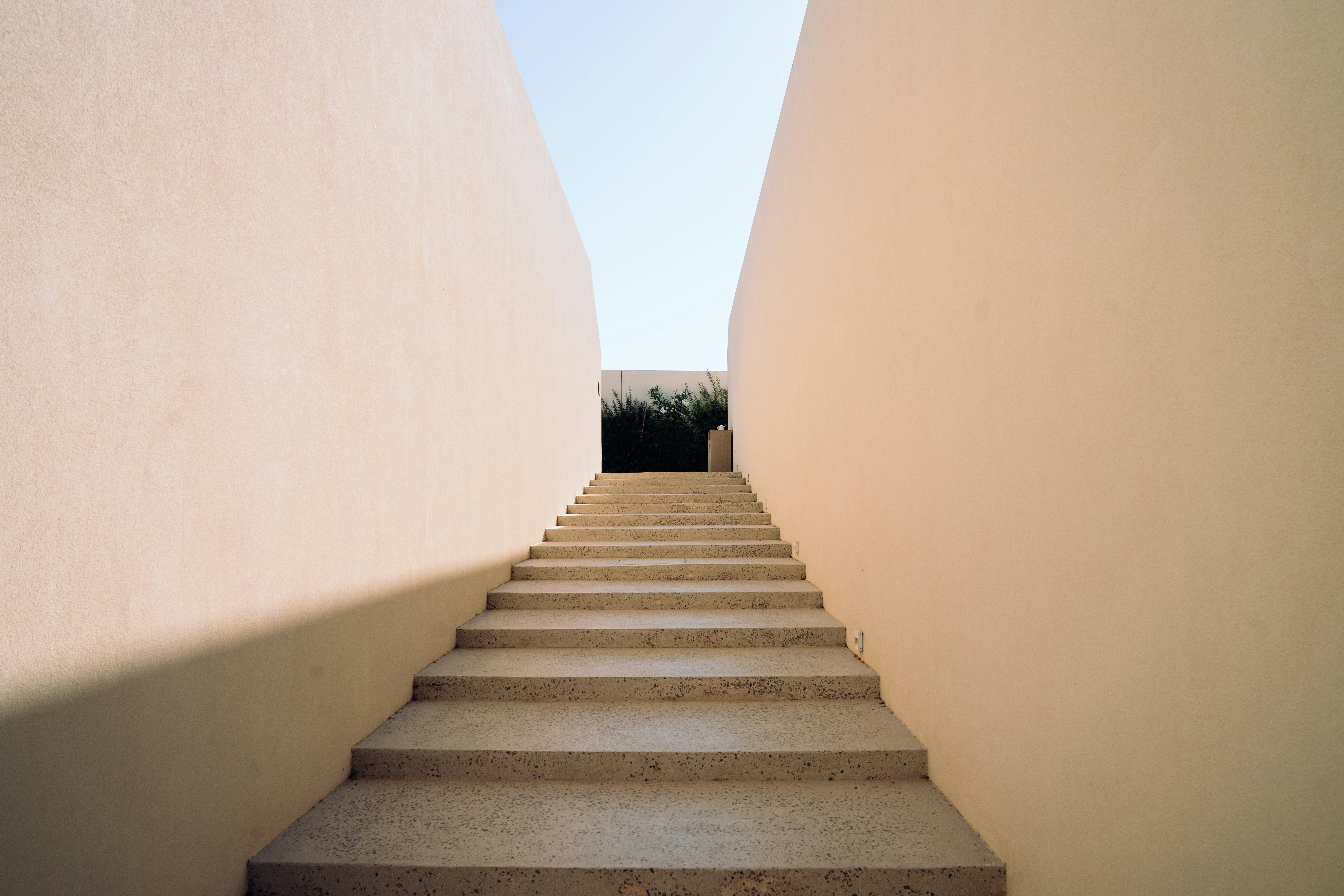 Ascending Light: A Sunlit Staircase Between Cream Walls