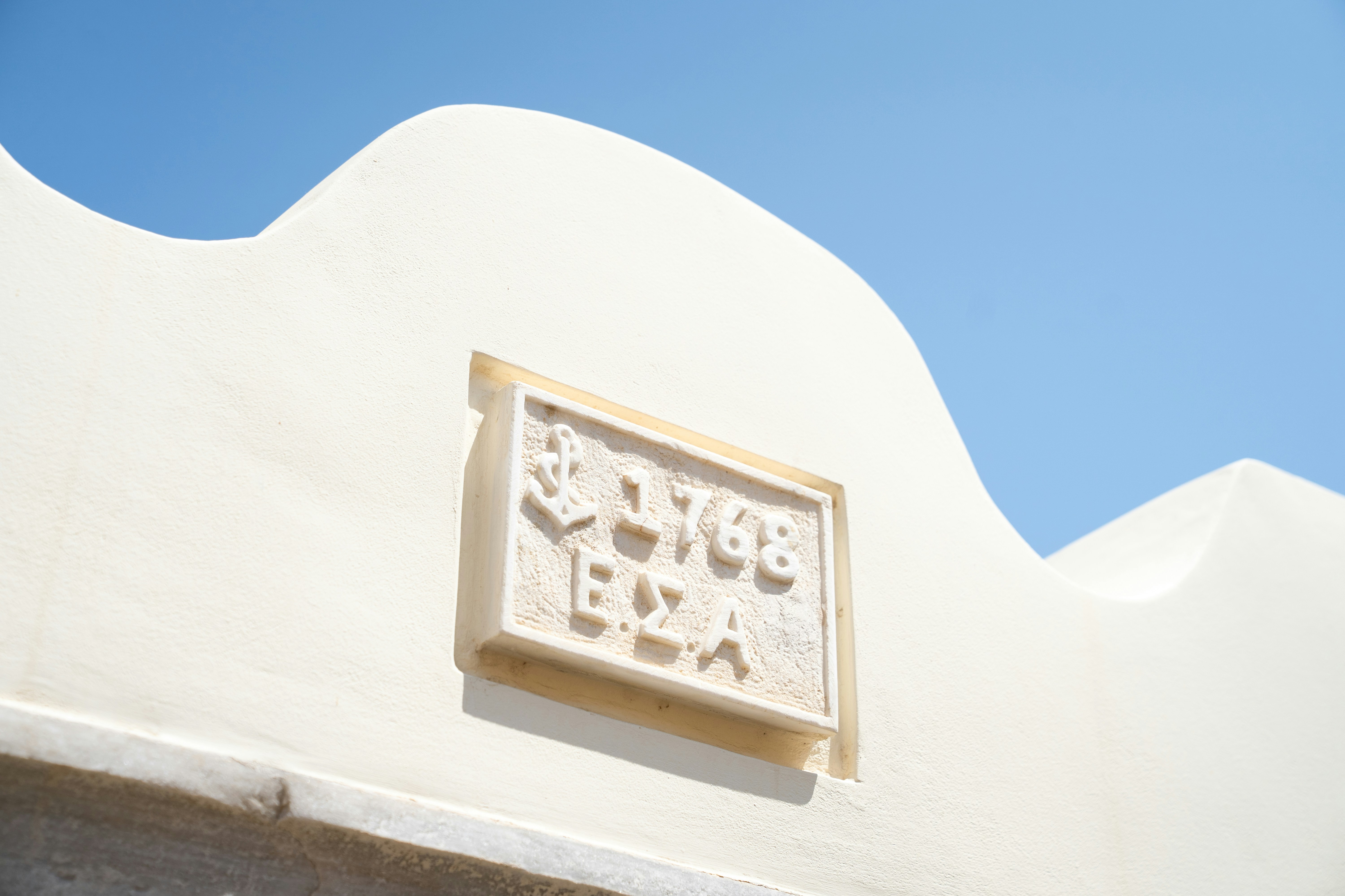 White Facade with Relief Plaque under Blue Sky