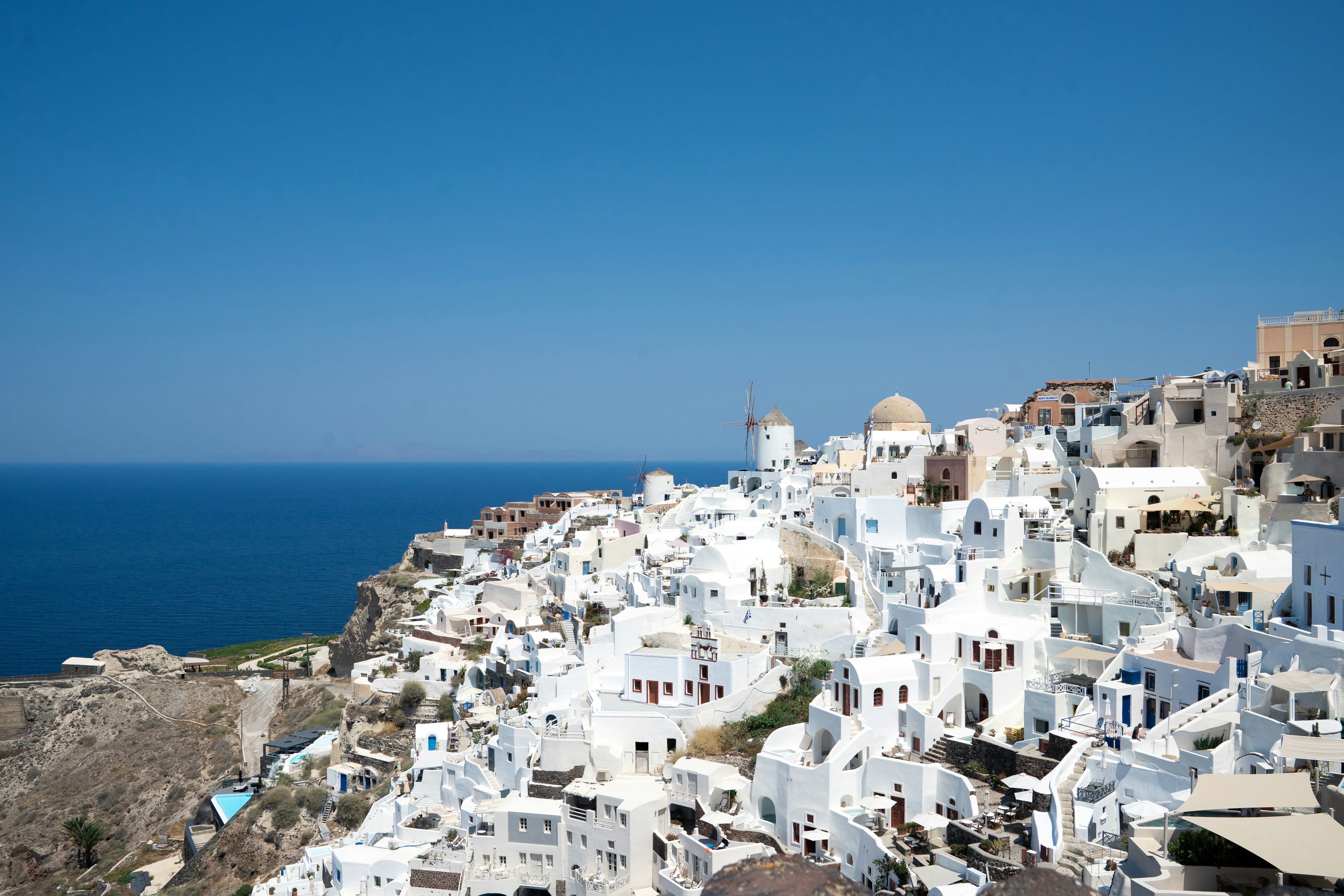 Whitewashed village ribbons along the cliff edge under Aegean blue