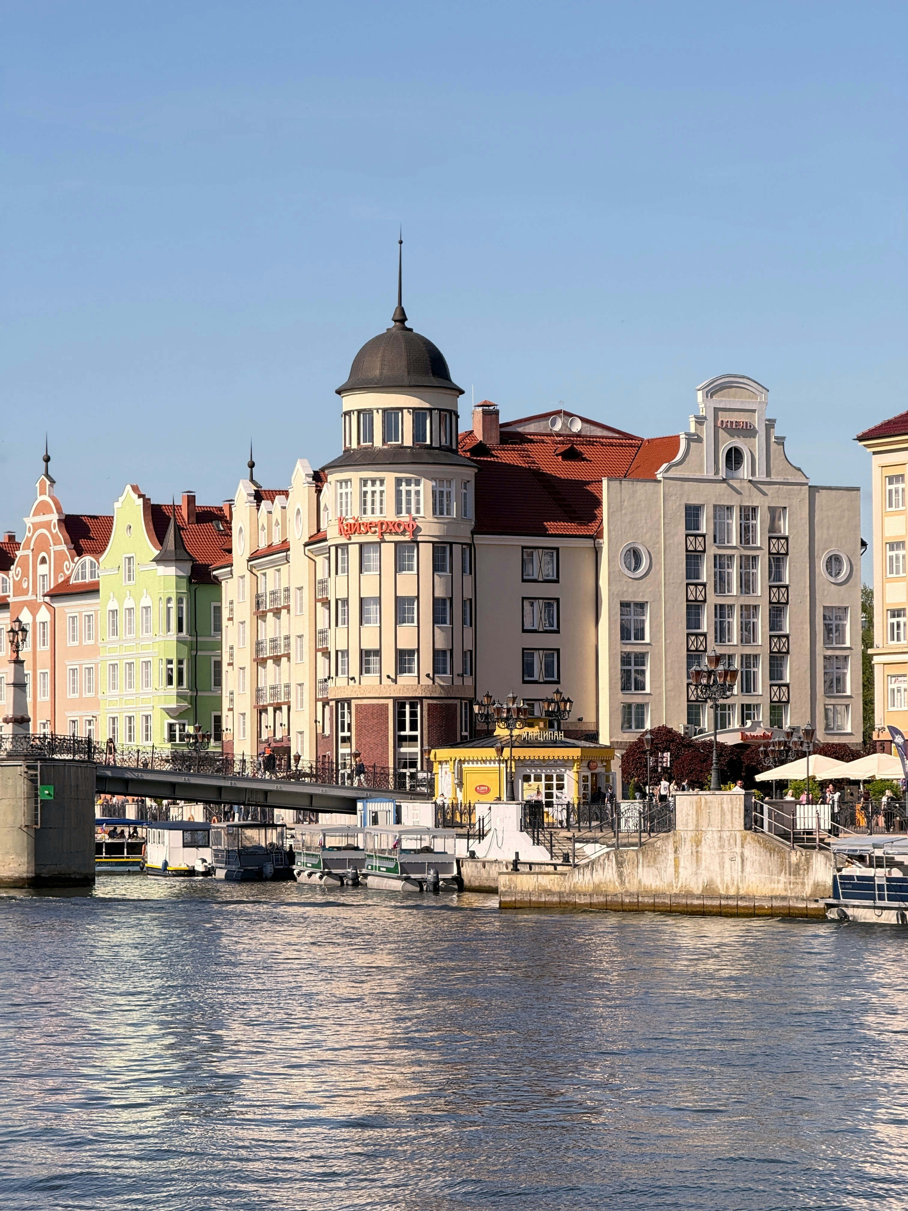 Colorful riverside facades line a sunlit quay beneath clear blue skies