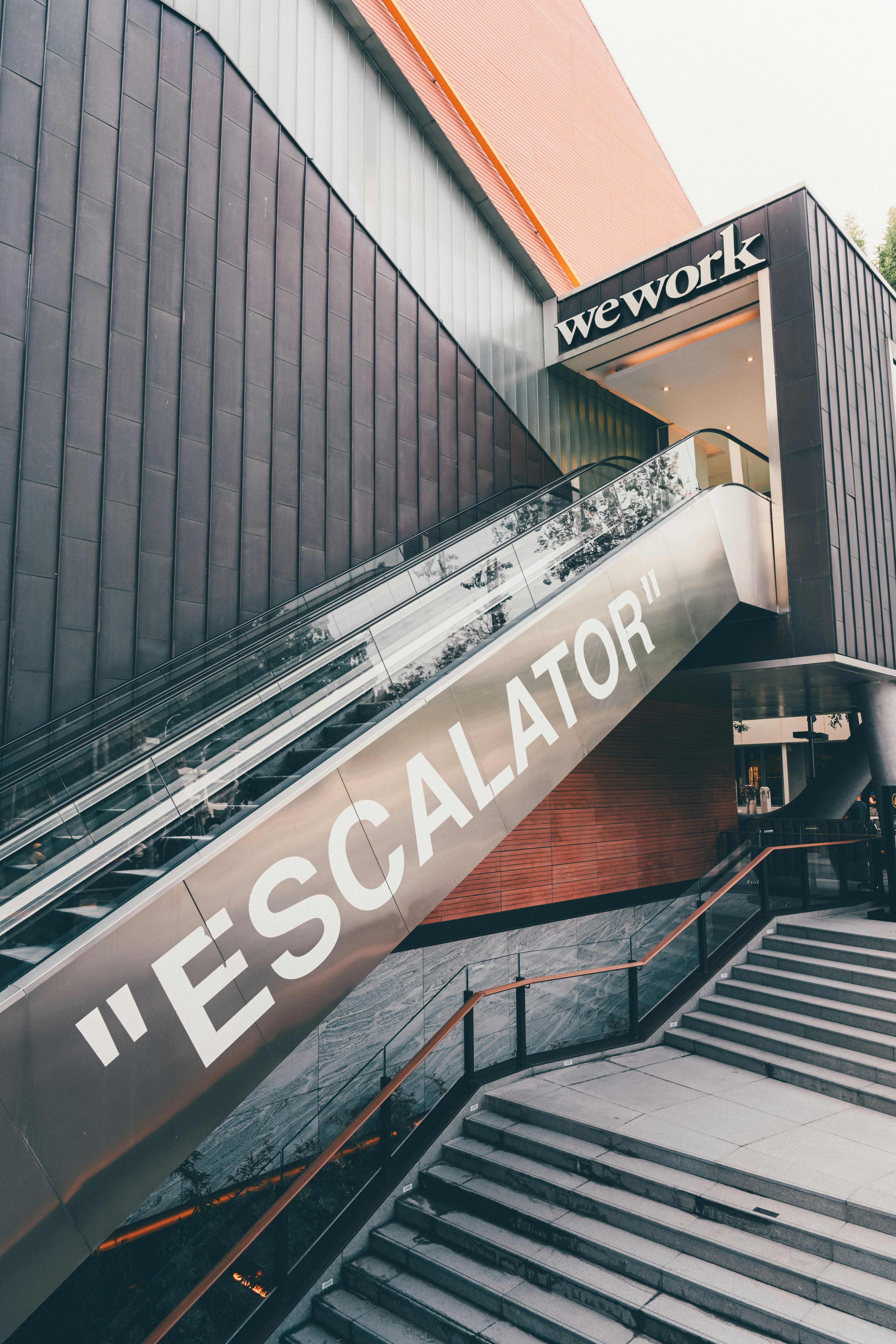 WeWork escalator ascent to the bold 'ESCALATOR' at a modern storefront