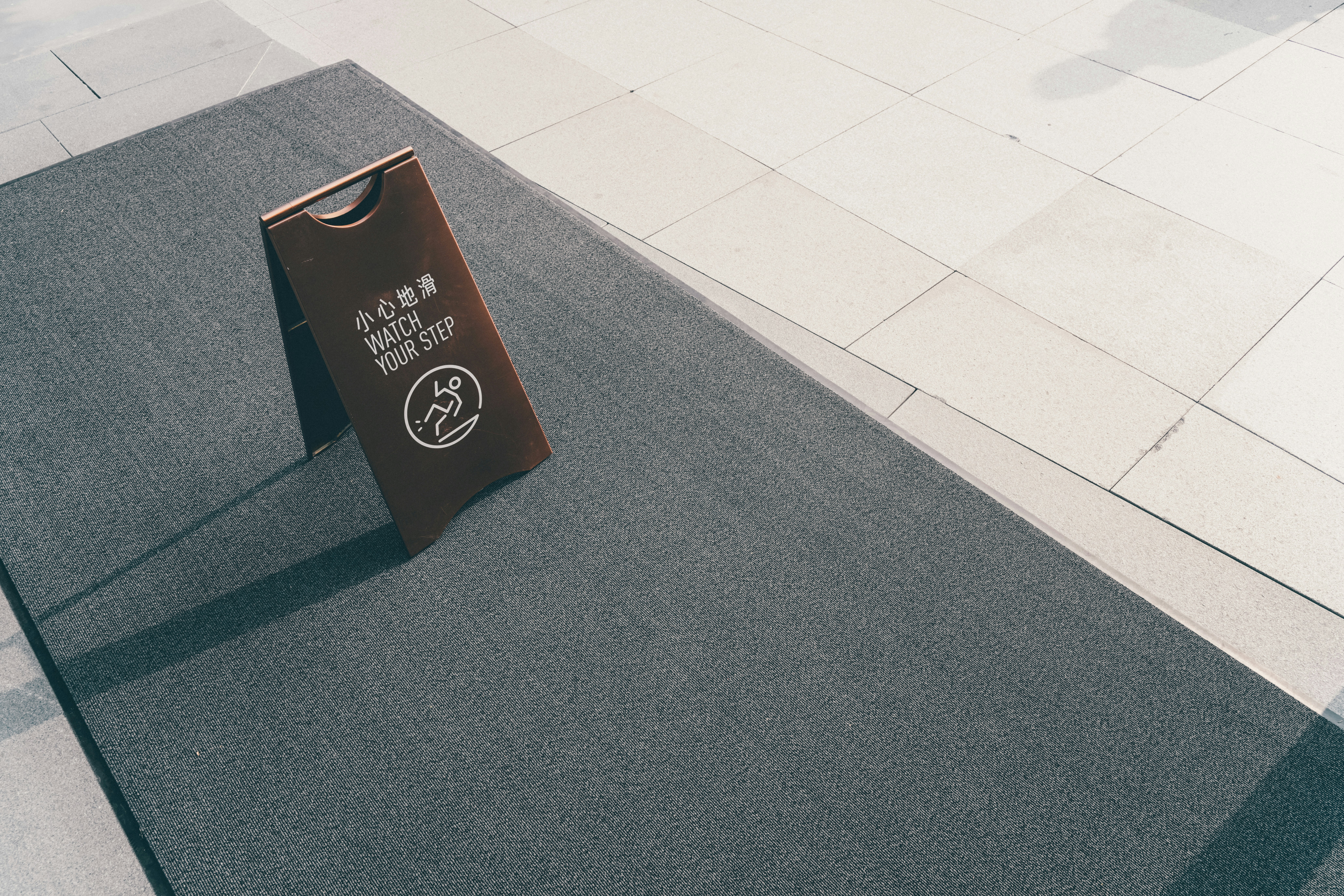 Step in Shadow: A Sign on a Slanted Mat