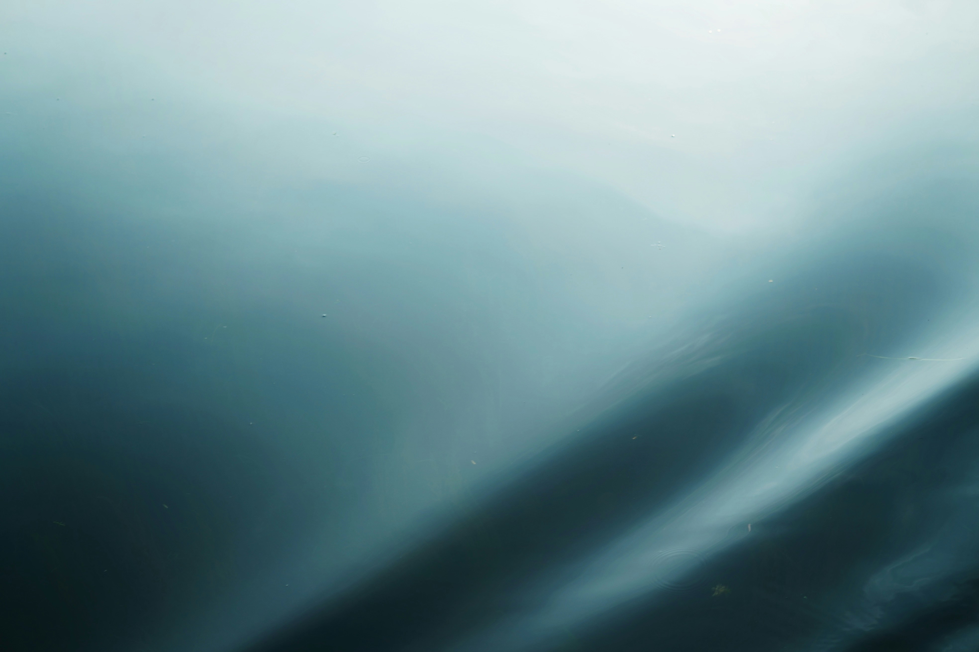Abstract blue-toned gradient with soft, sweeping light patterns suggesting water or sky, devoid of a clear subject; appears as a tranquil color-field/gradient with subtle diagonal highlights.