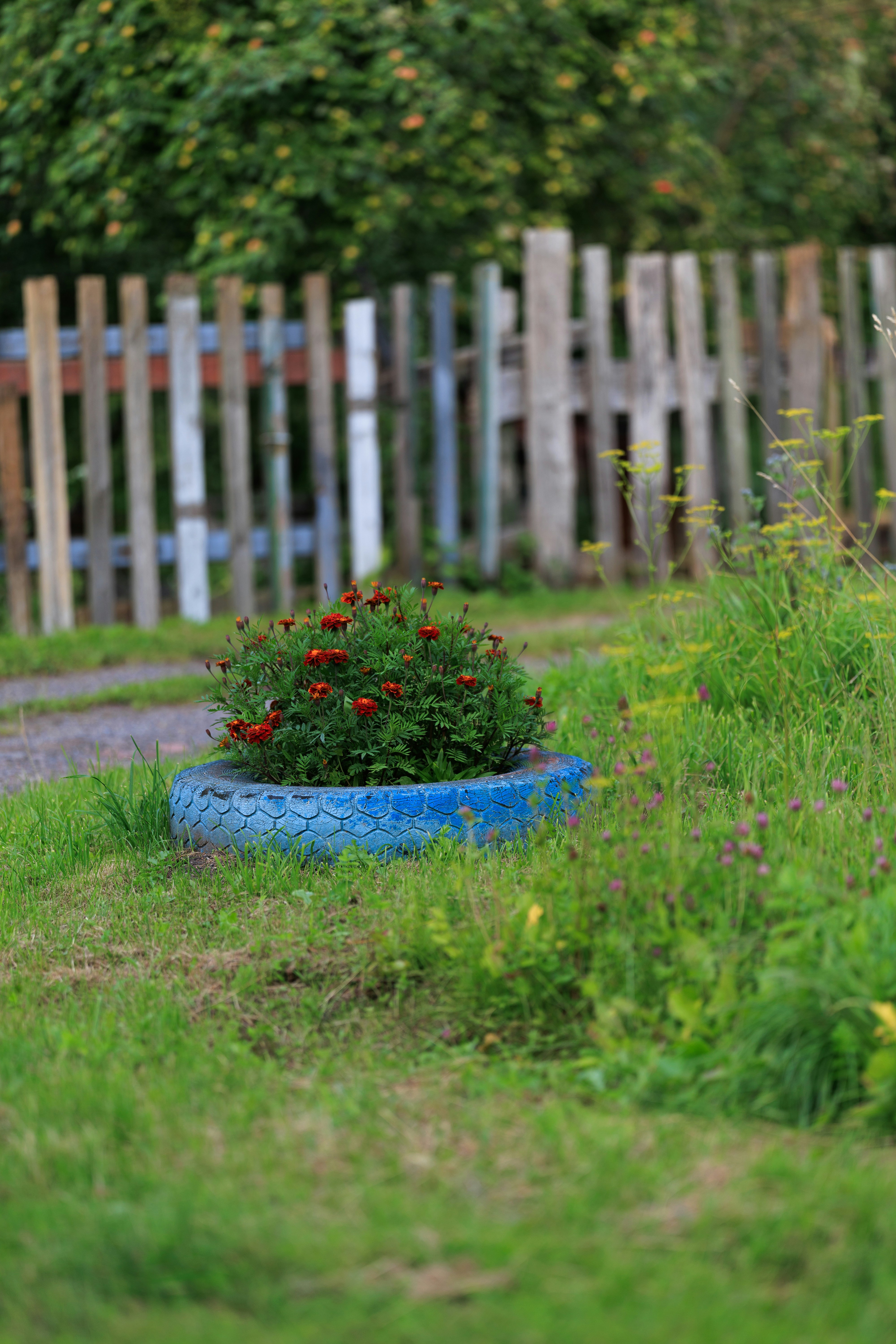 Blue-tired planter of red blossoms in a garden clearing