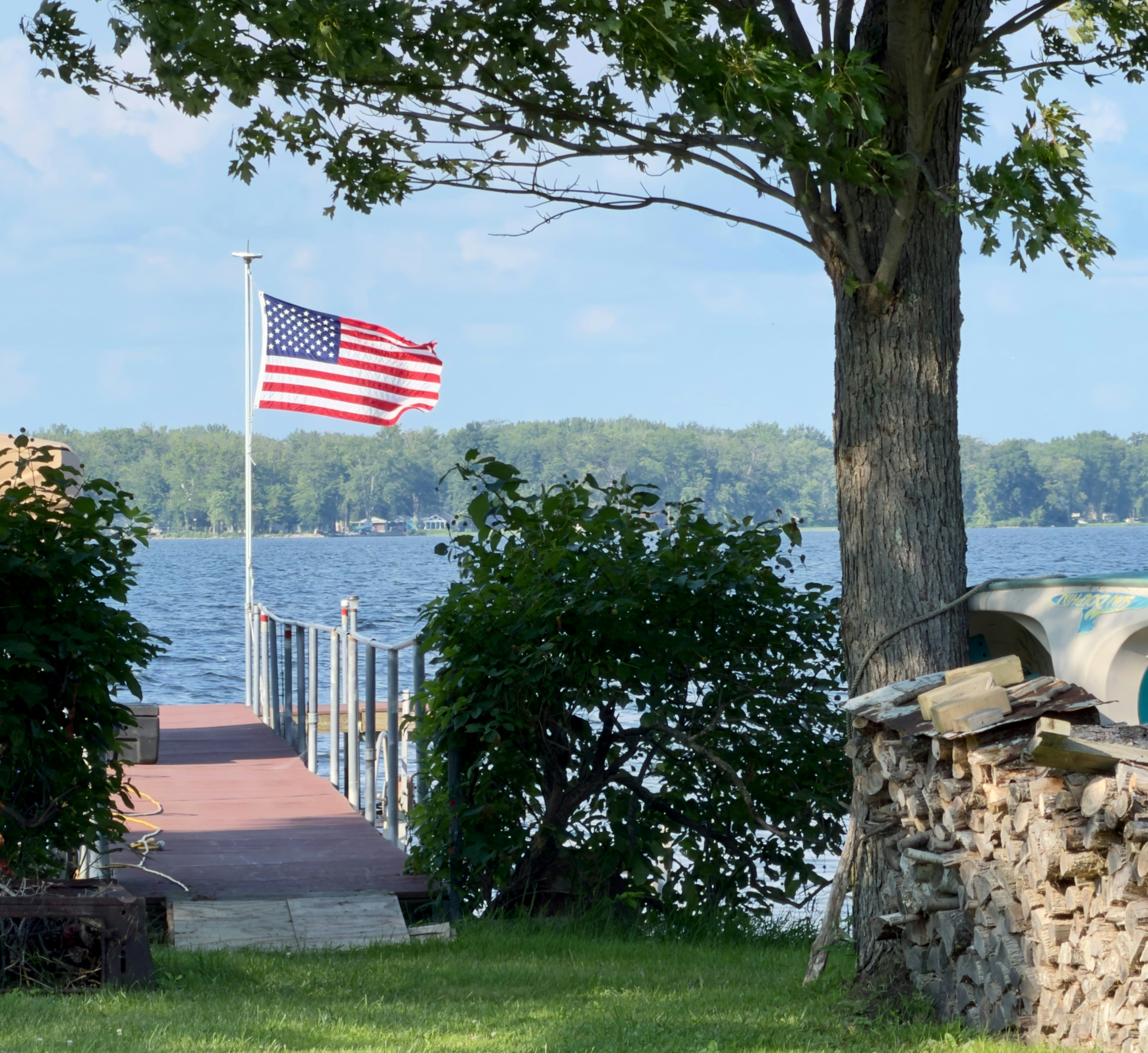 Flag at the Jetty: Quiet Lakeside Portrait with Stone Wall and Tree
