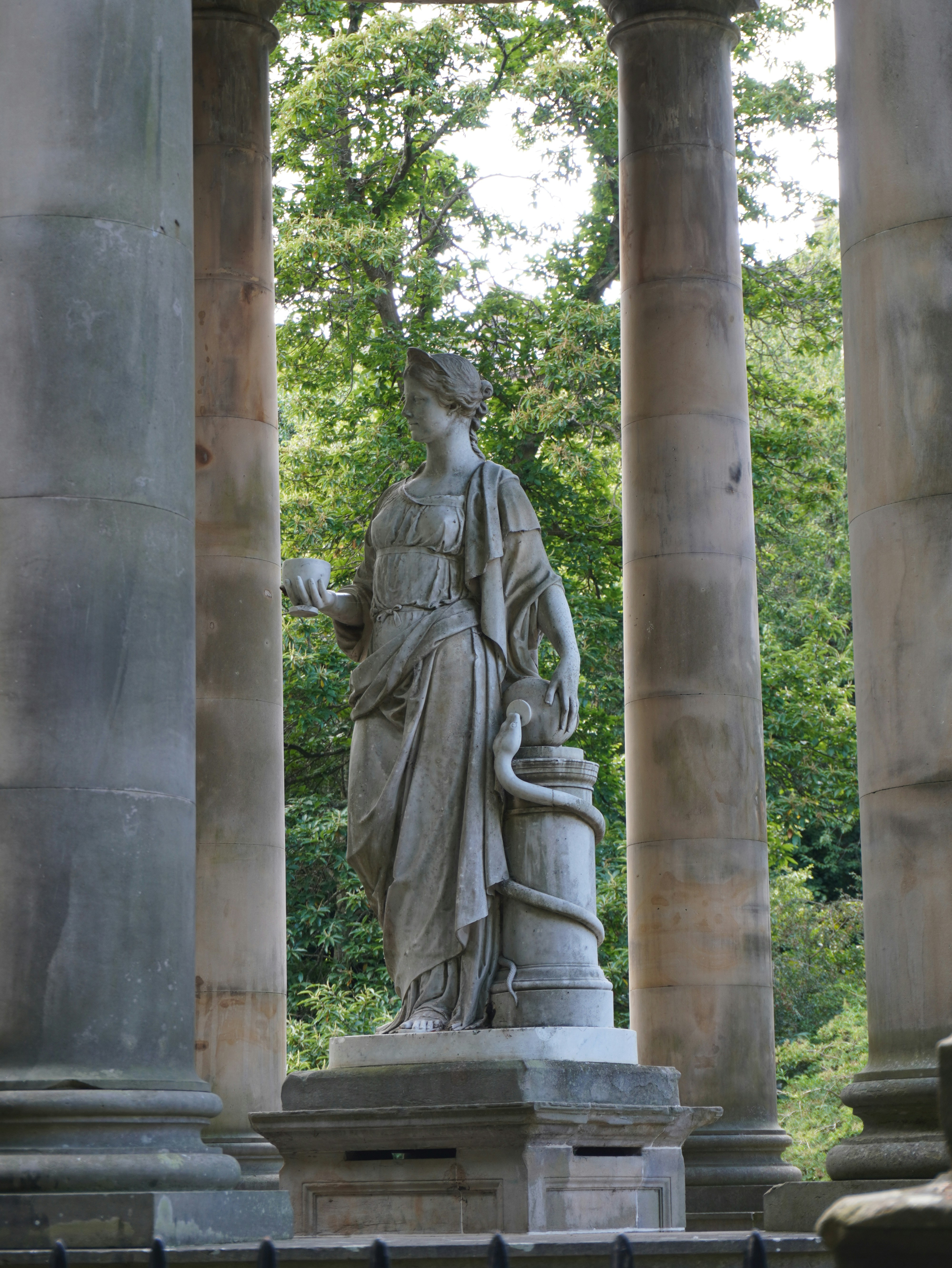 Statue Among Columns: a Classical Figure Framed by Dappled Greenery