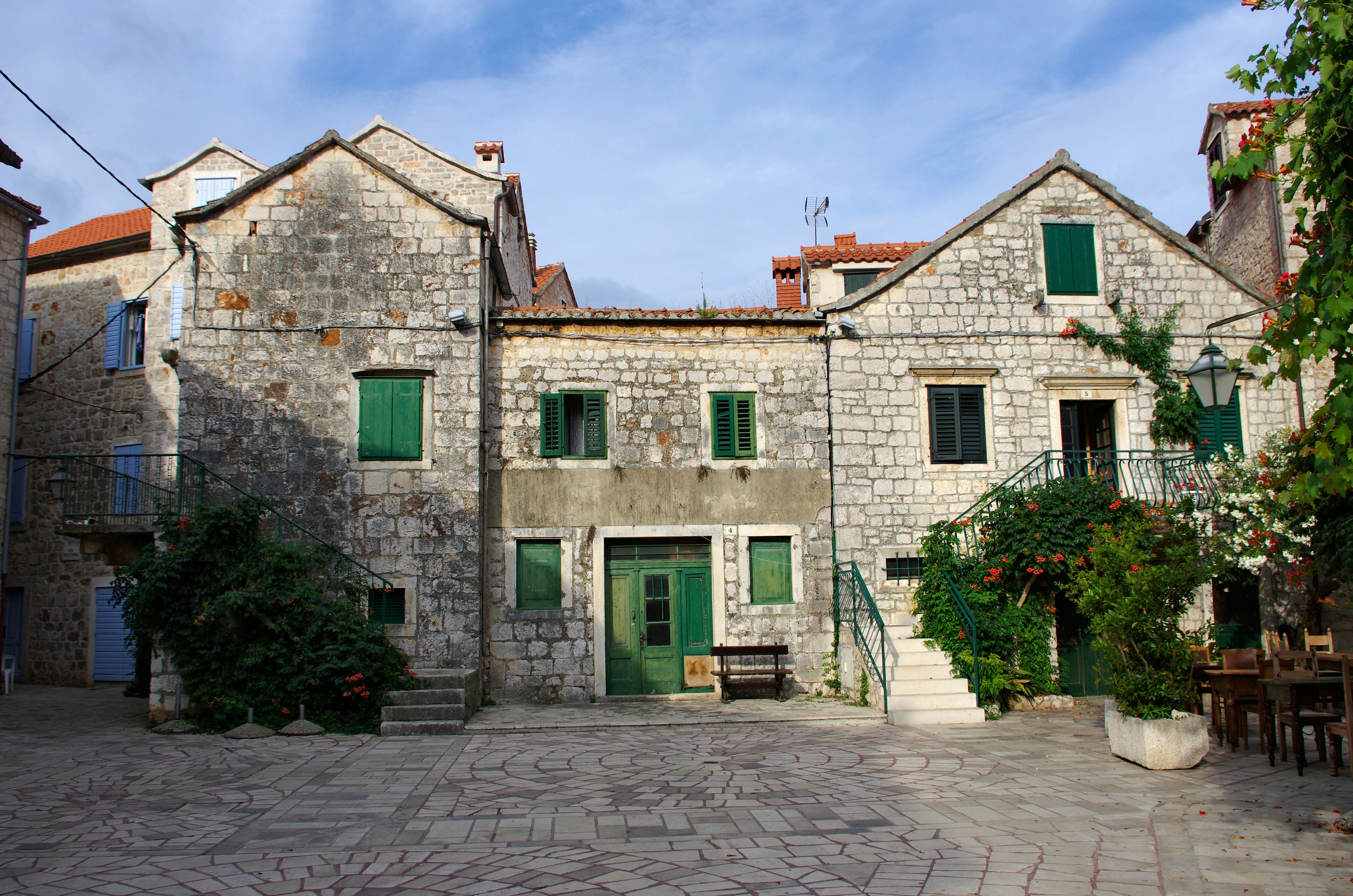 Stone façade Symphony: A Quiet Village Square with Green Shutters