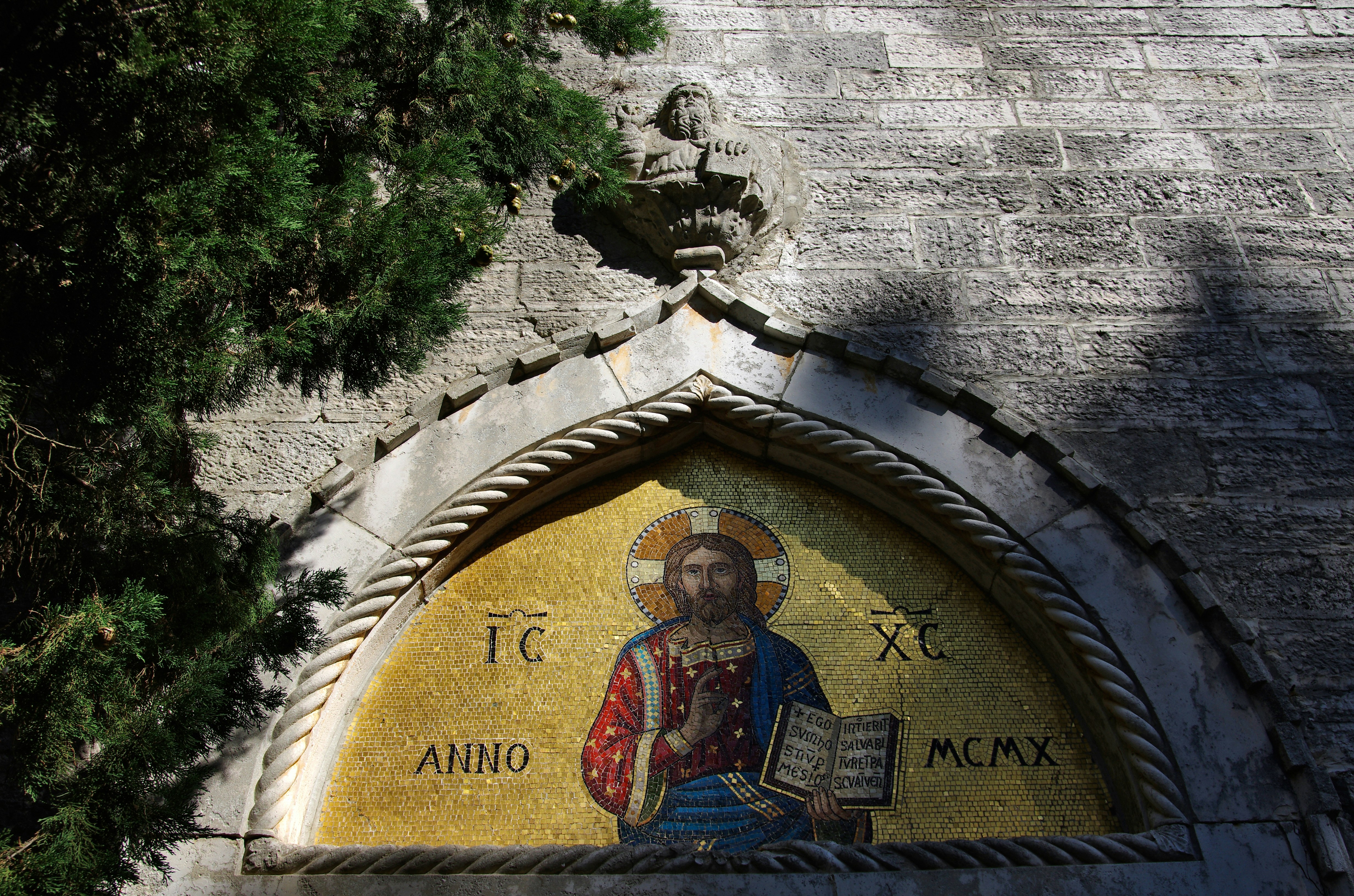 Mosaic Christ over Stone Arch: Centered Amidst shadowed Facade
