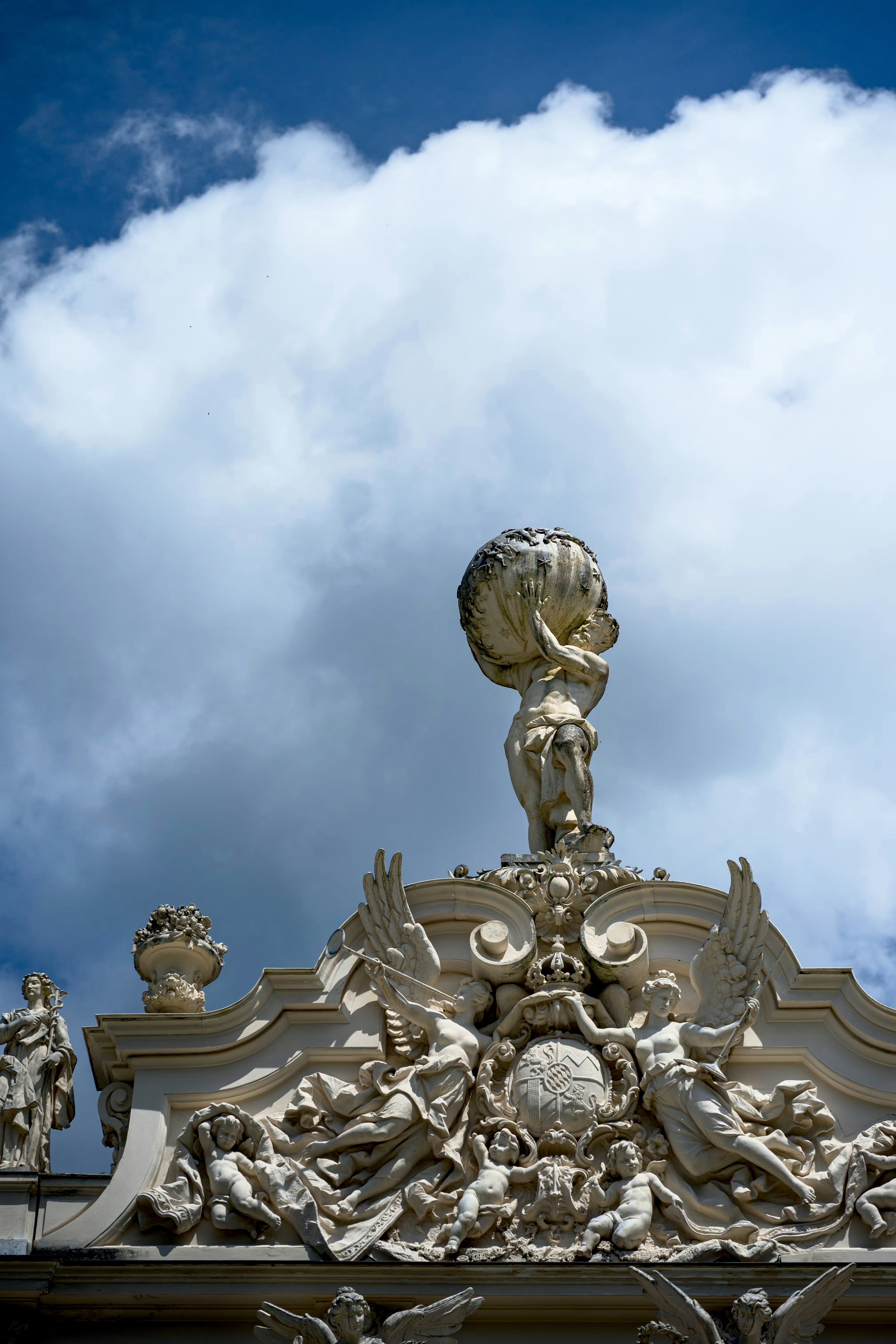 Winged Relief: A Carved Baroque Crest Against A Sky of Clouds