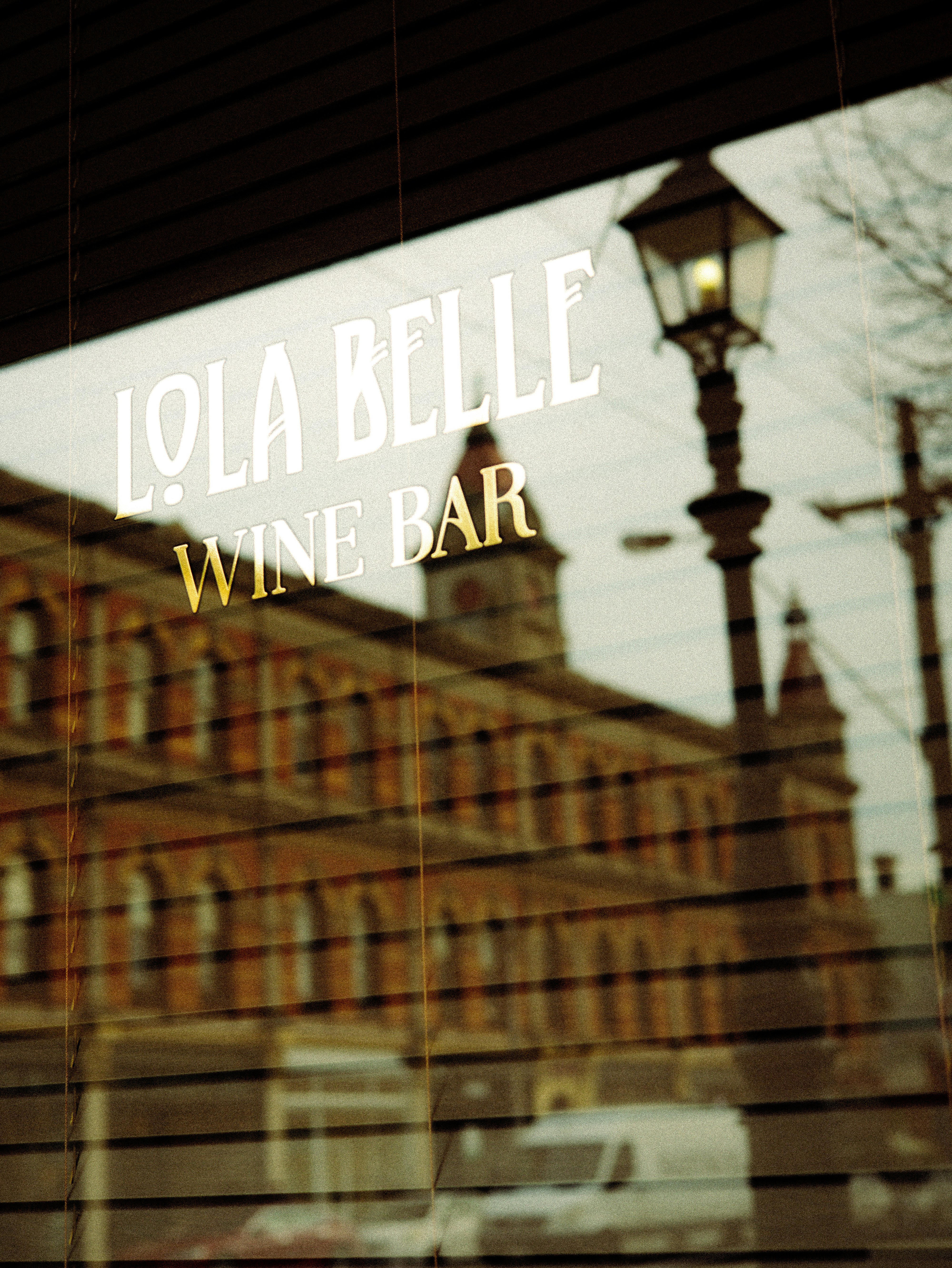 Reflection of Lola Belle: Glass Sign, Streetlamp, and City Fade