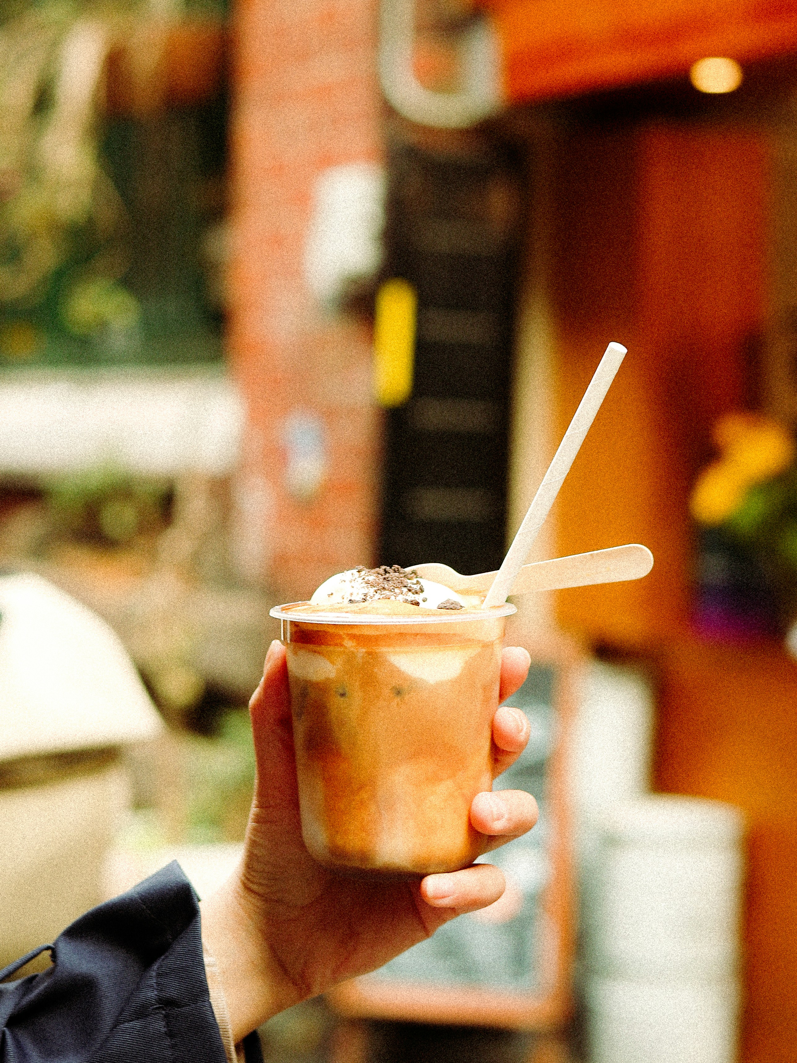 A creamy dell of caffeine: iced drink held aloft in a sunlit street