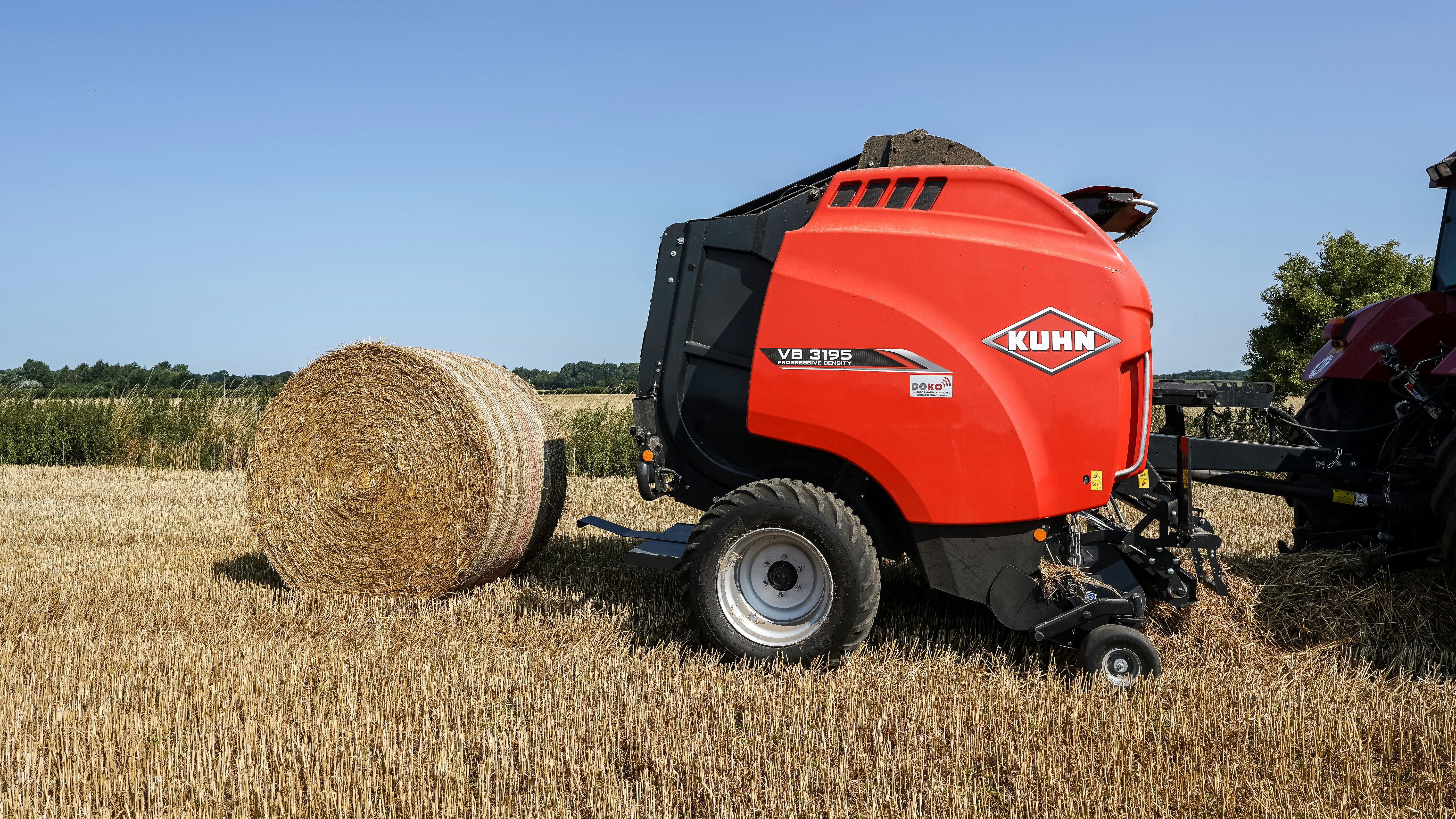 Harvested Field and Red Balebine: A Kühn Harvester in Golden Stubble