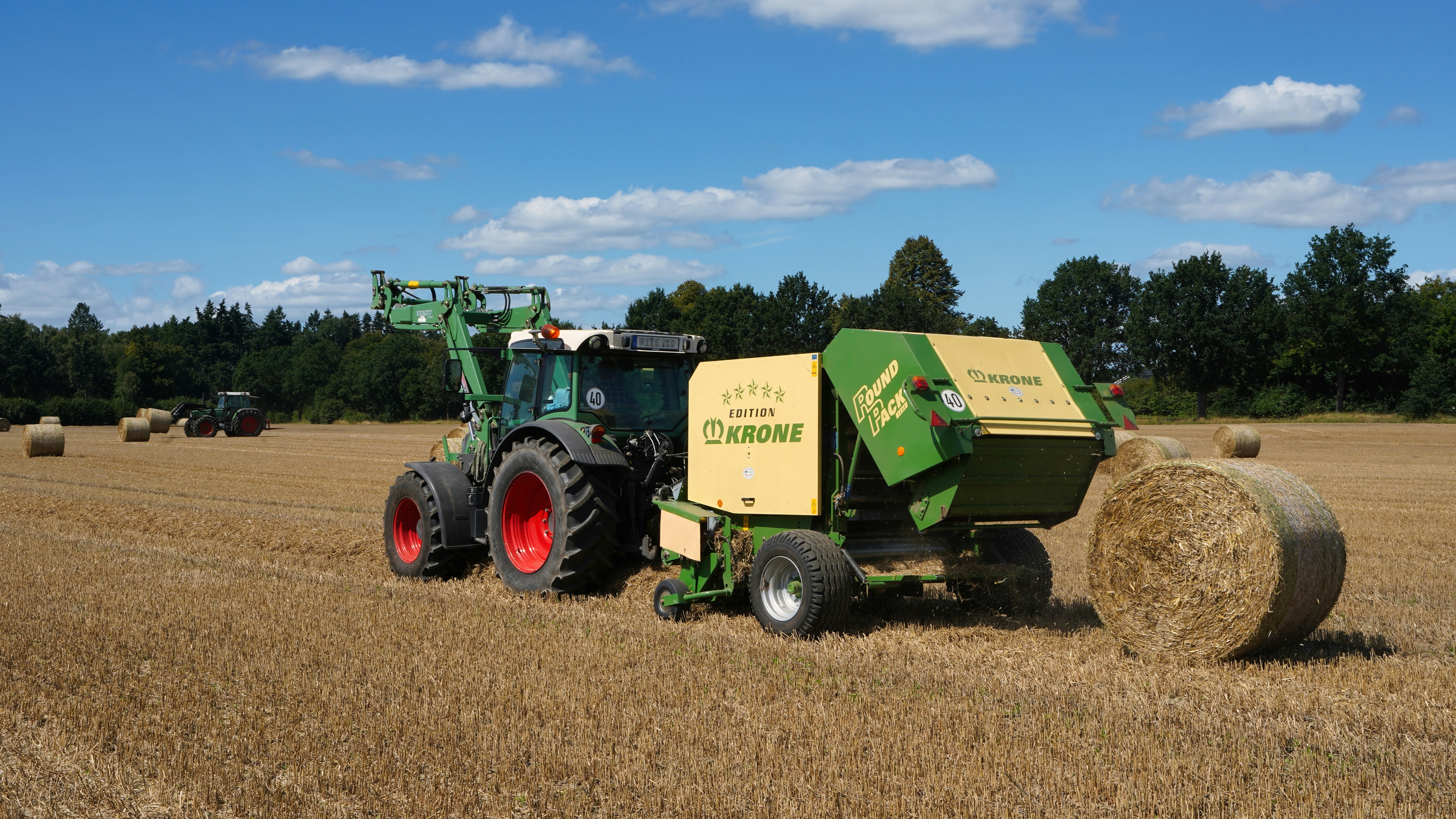 Green Tractor with Hay Harvester in a Golden Harvest Field