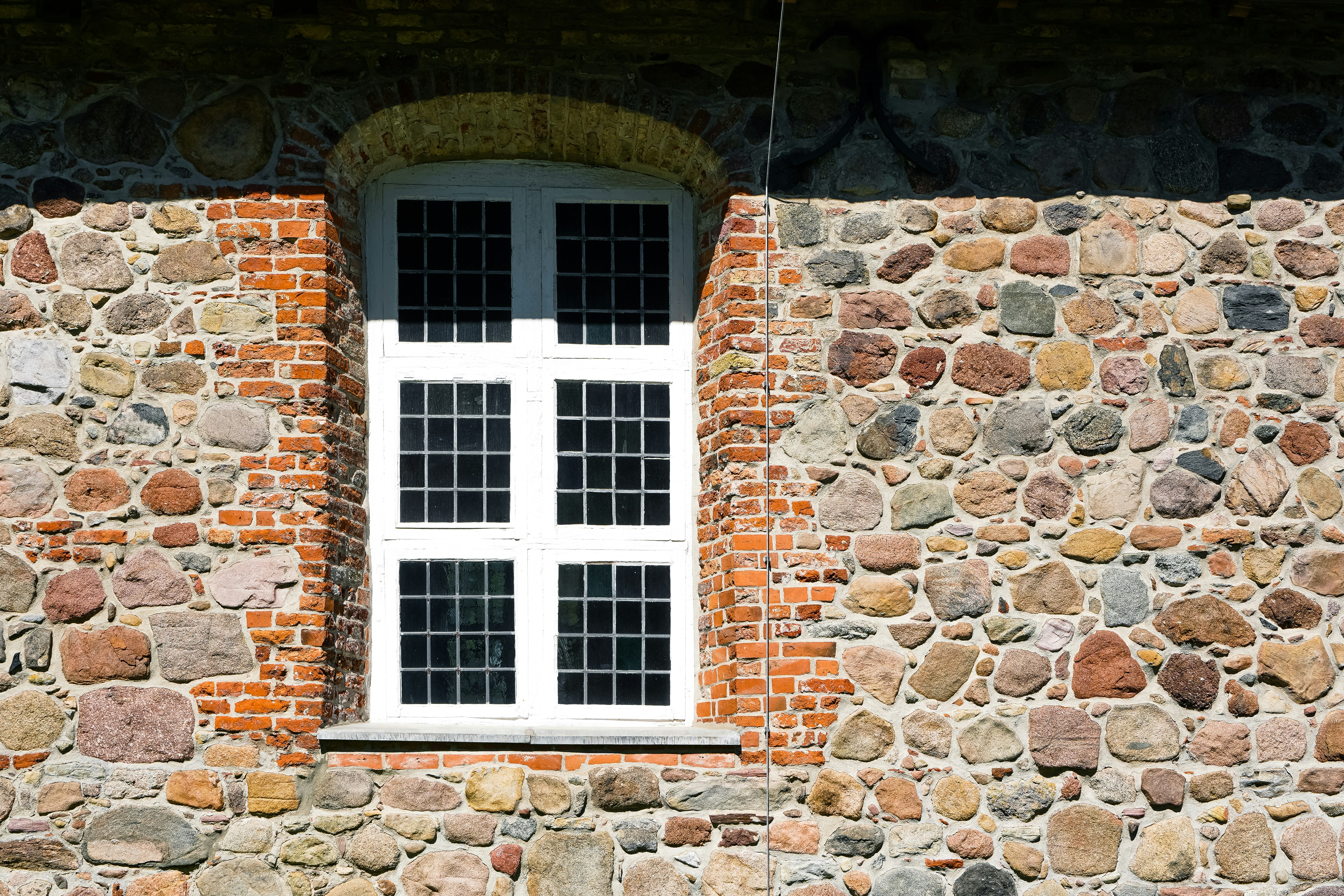 Stone window across a sunlit brick-framed wall