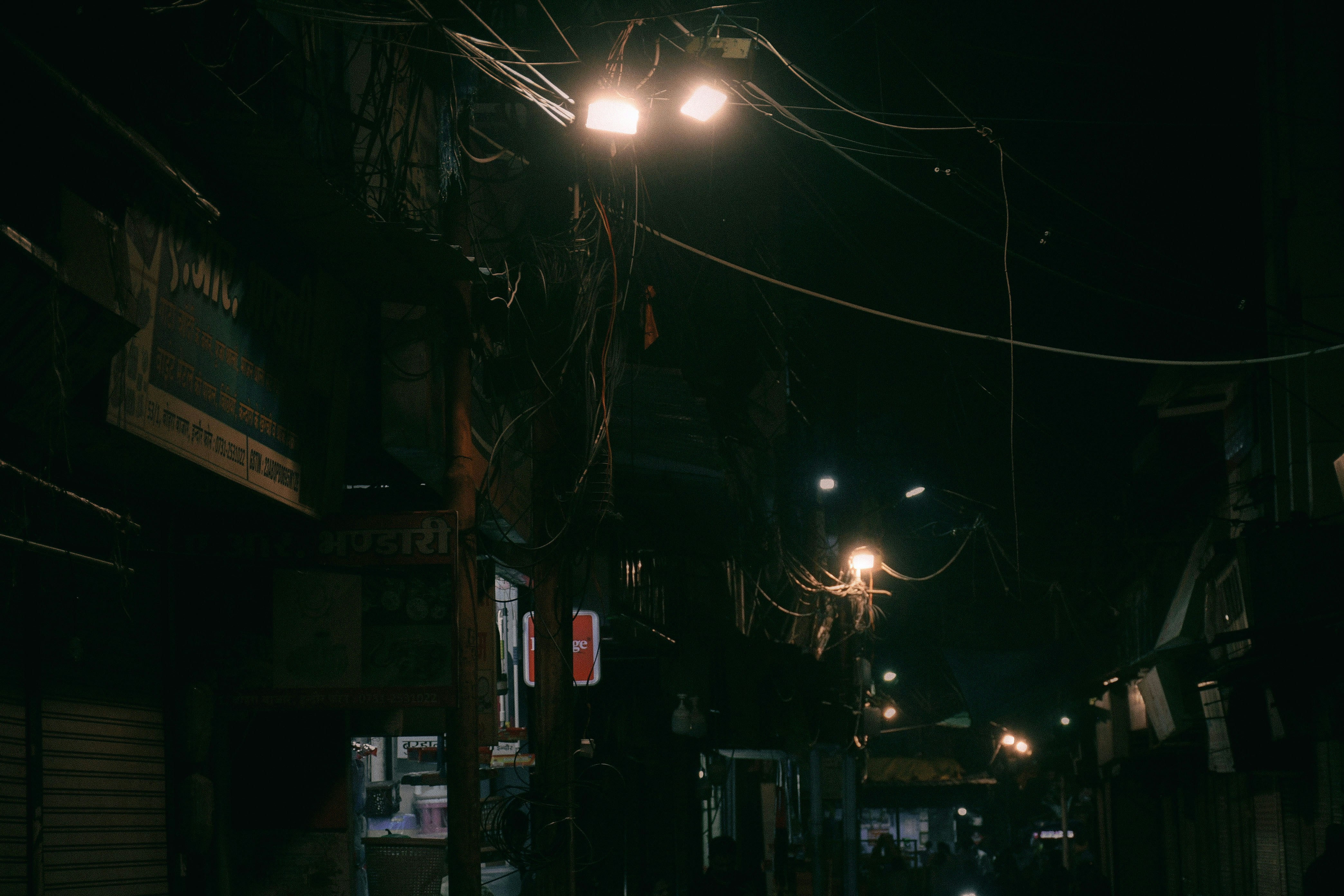 Night Market Glow: Dim Lanterns and Wires in a Narrow Alley