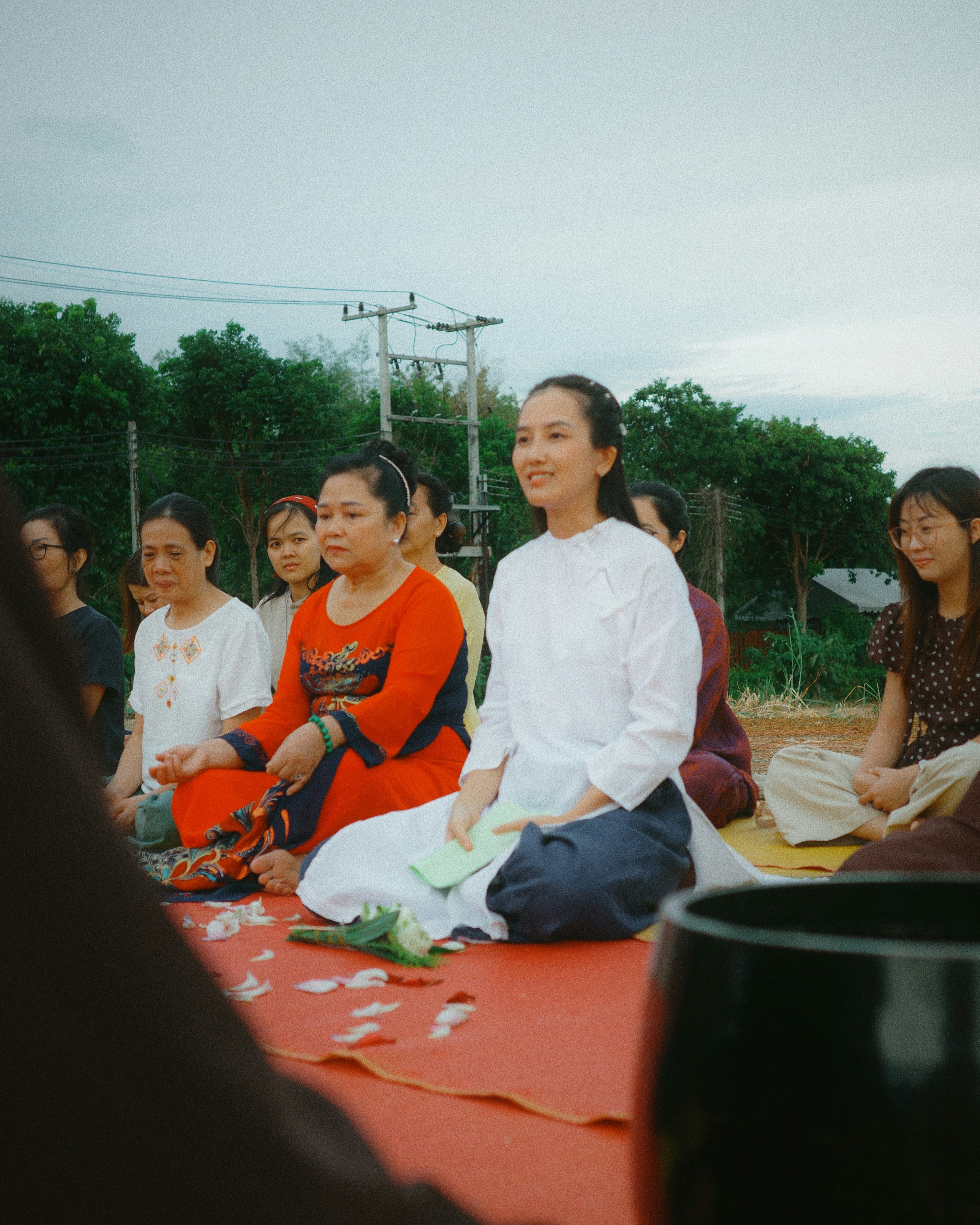 Centered Woman in White: Quiet Meditation During Outdoor Gathering