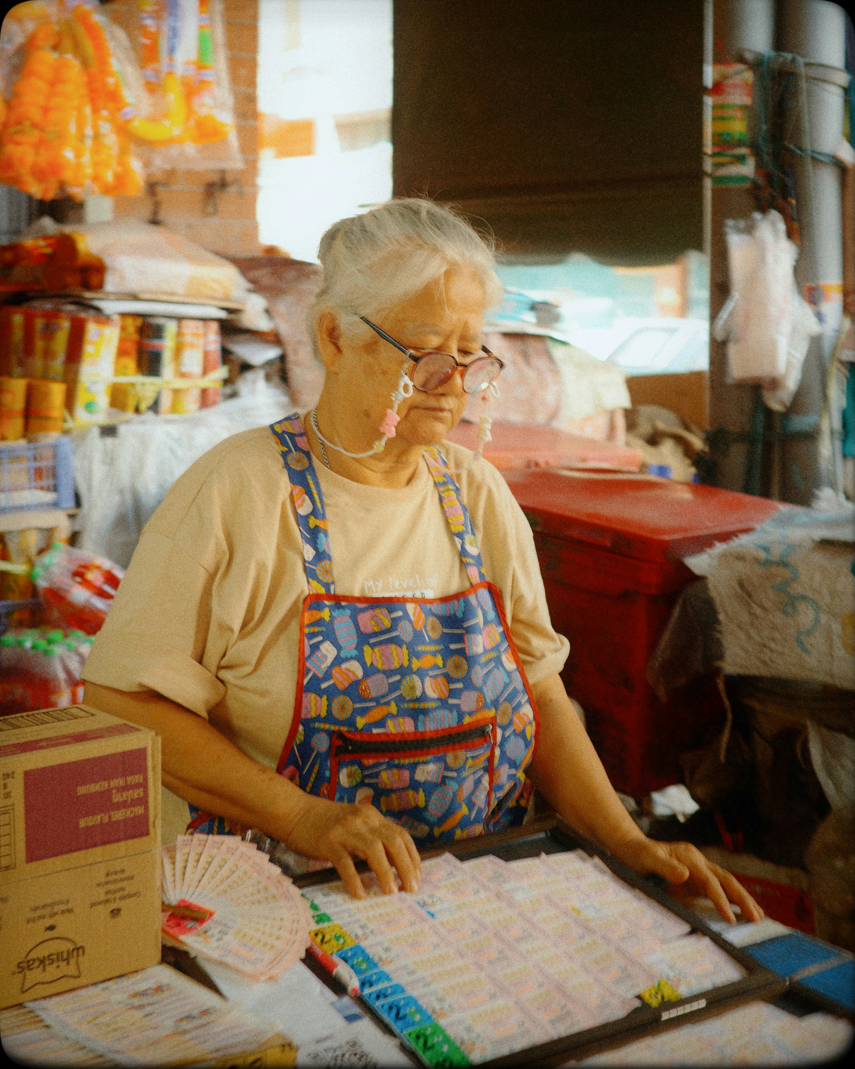 A seasoned vendor at a busy market stall, counting colorful call cards