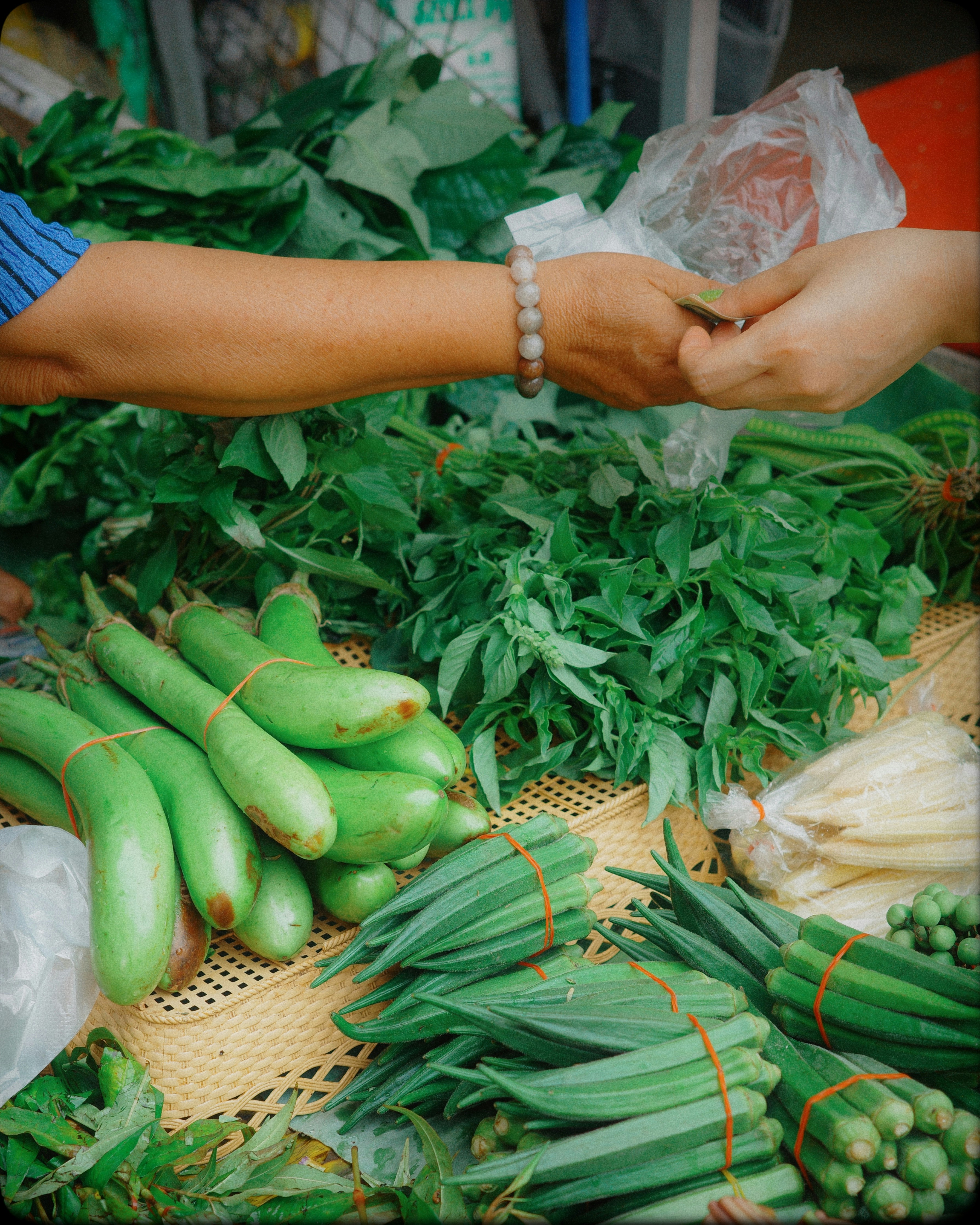 Hands Exchange Over Fresh Produce at a Market Stall