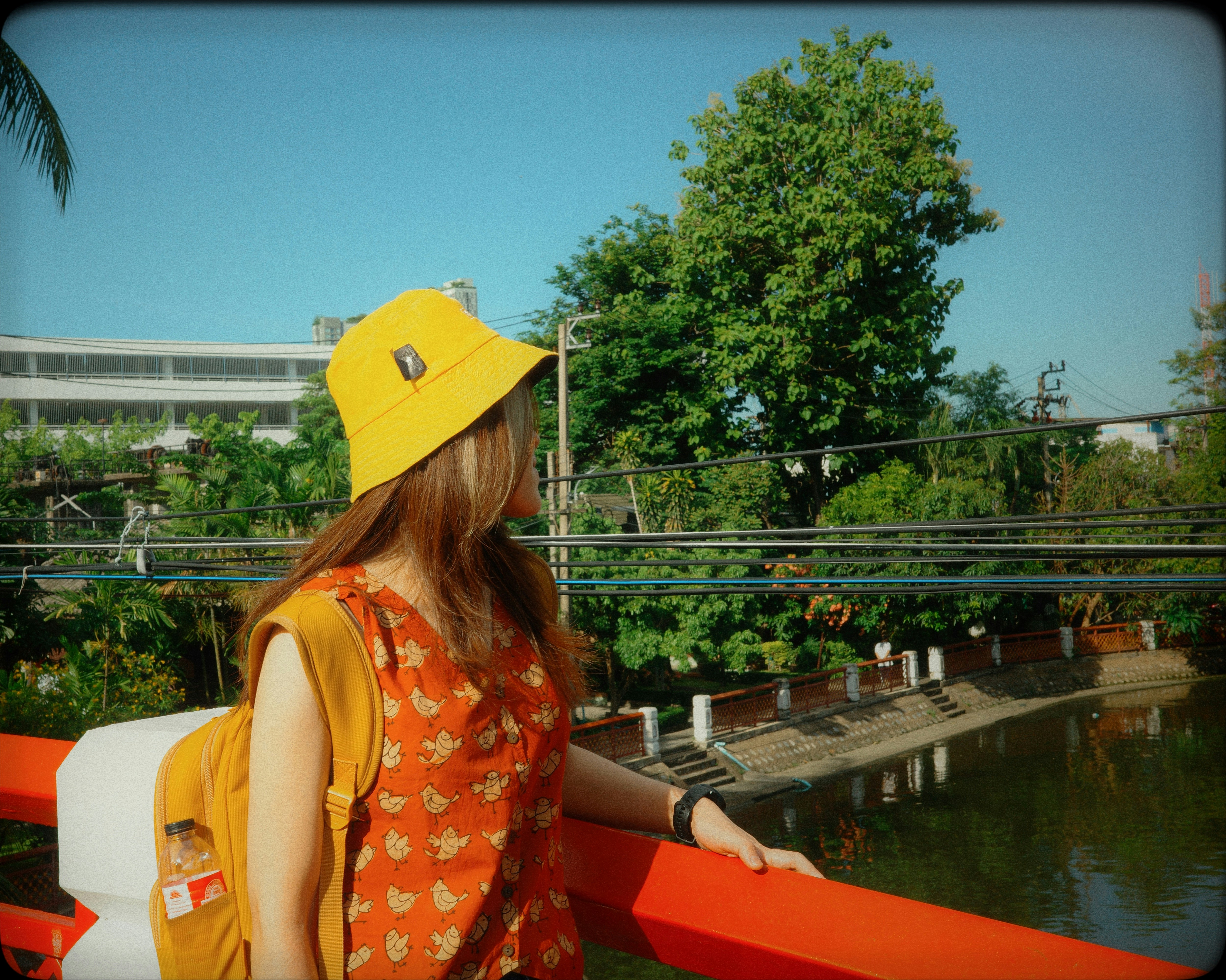 Sunlit Voyage: A woman in a yellow hat on a riverside bridge
