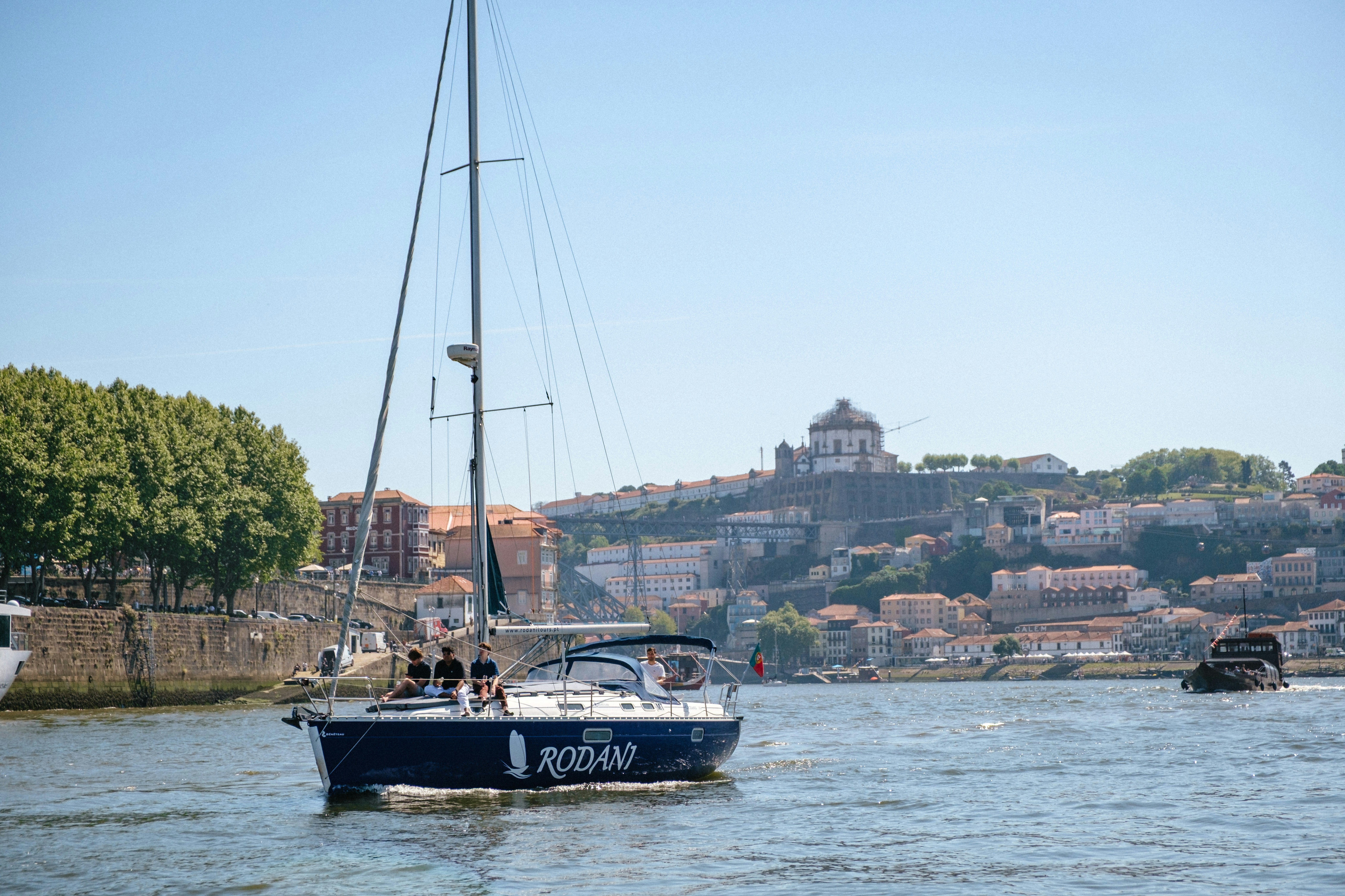 Sailing through a coastal cityscape: a blue yacht glides past historic shores