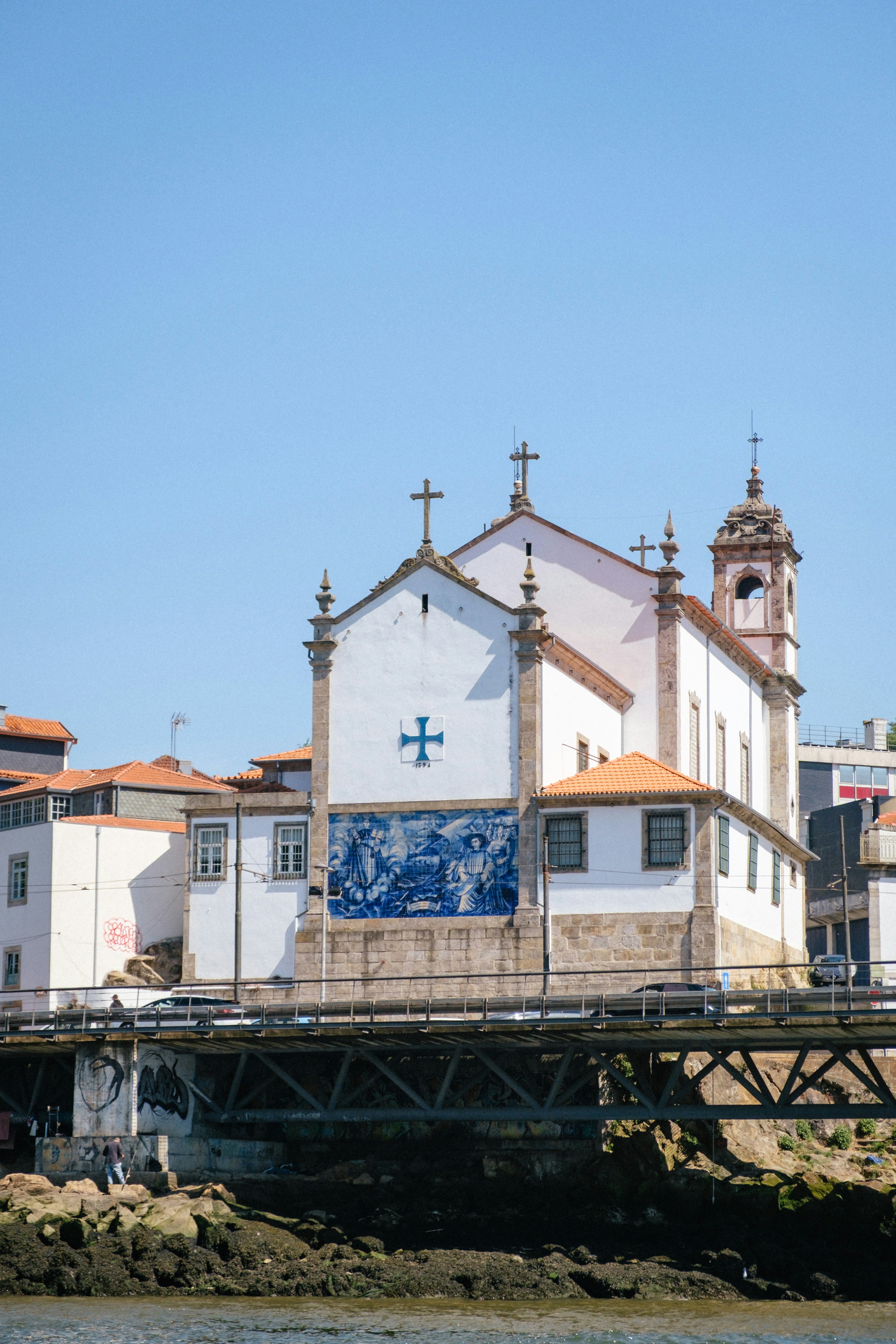 White-walled church on the riverfront bridge under a clear blue sky