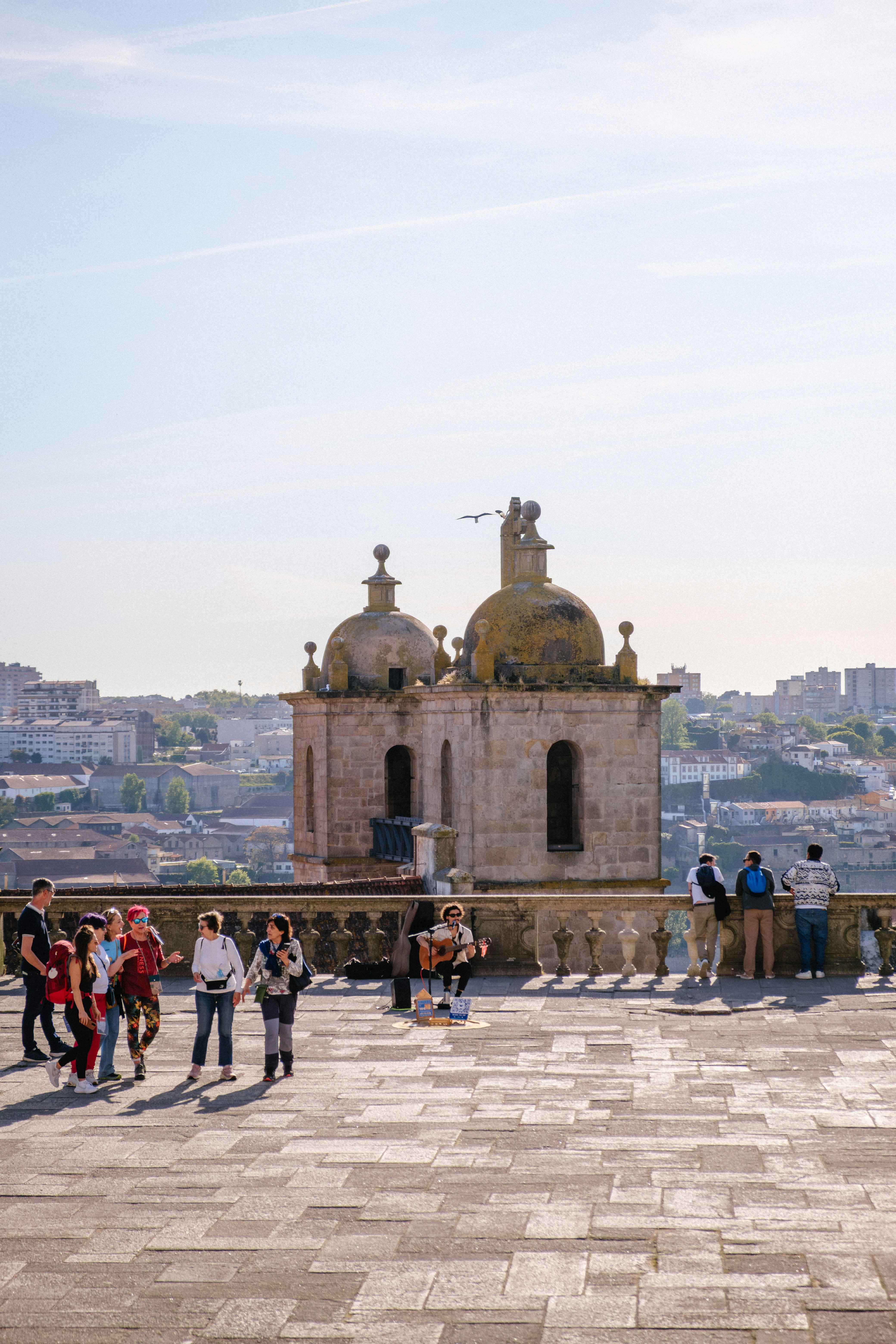 Rooftop Mosaic: Visitors and a Distant City on a Sunlit Terrace