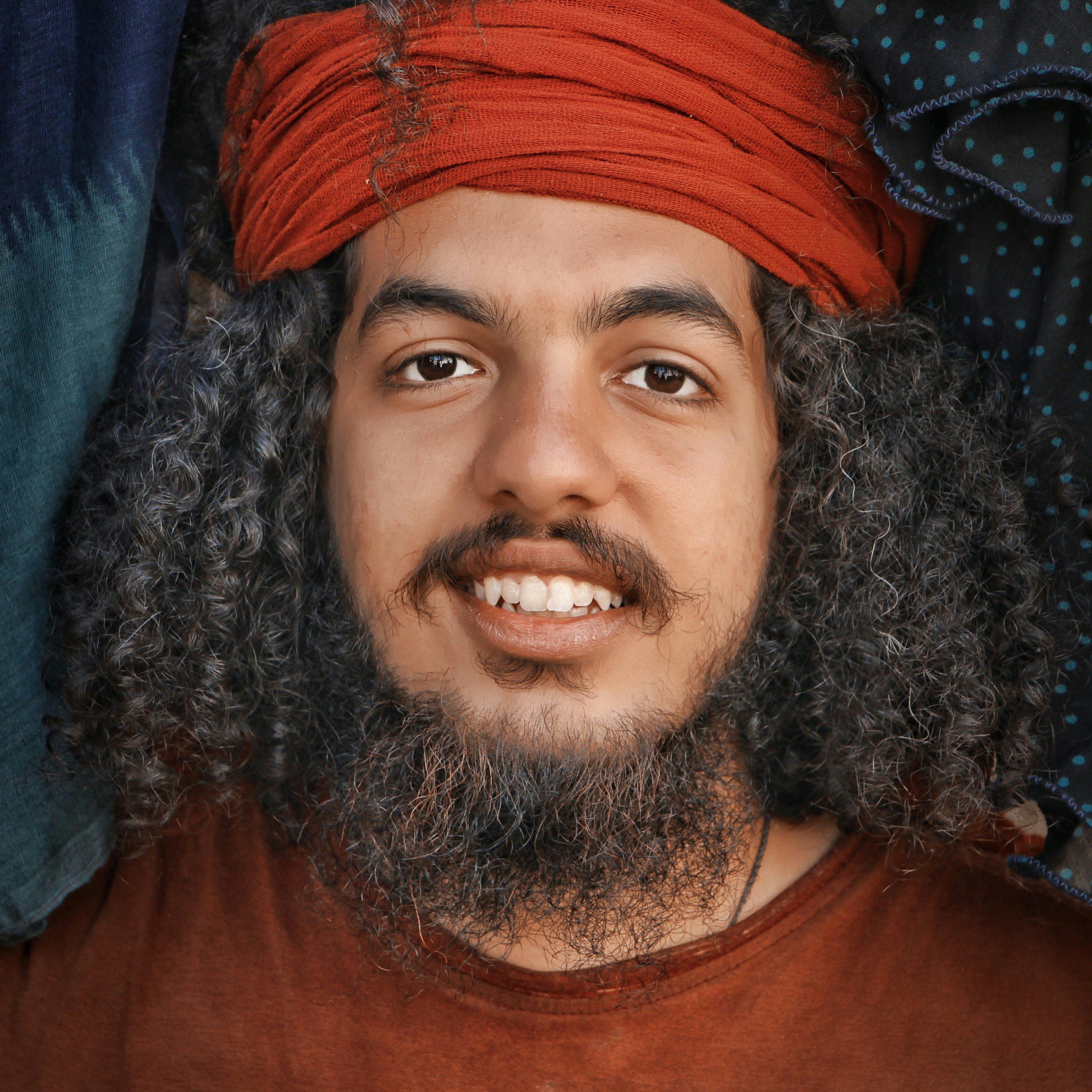 Coiled curls and a warm smile: portrait of a young man with a red headwrap