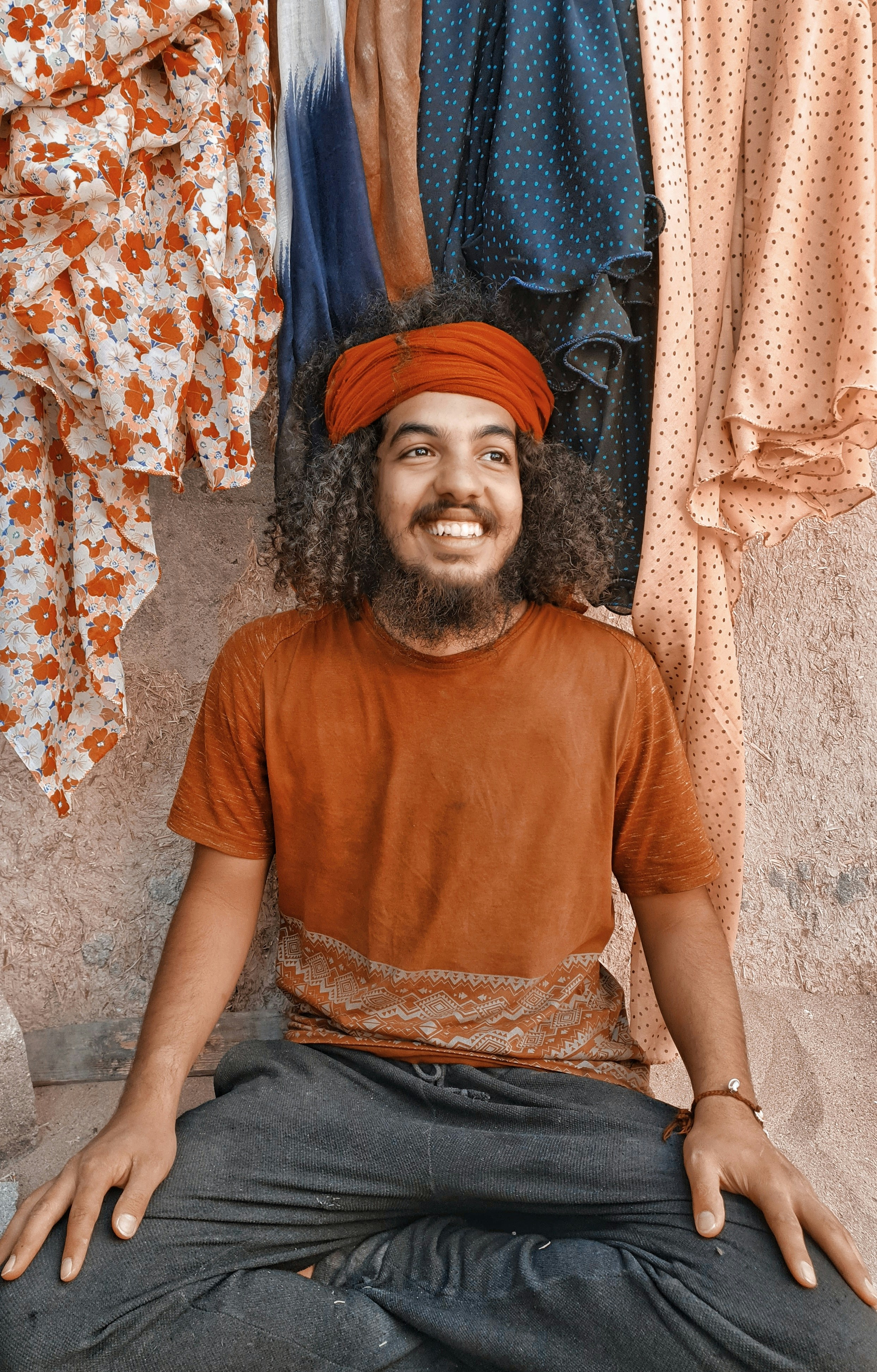 Smiling in Colorful Threads: A Portrait Among Draped Fabrics